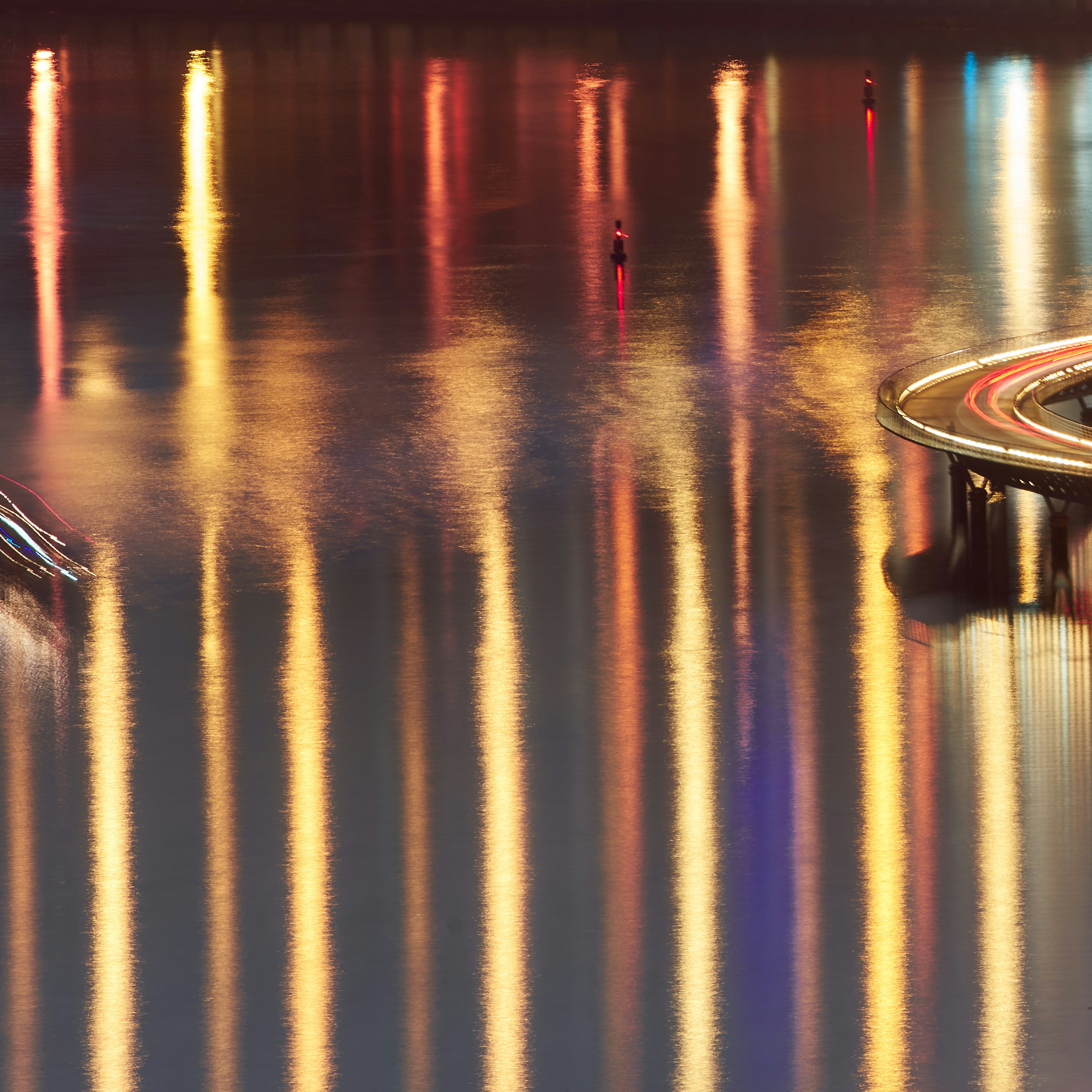 Vertical Neon Echoes Over Quiet Water by a Curved Pier