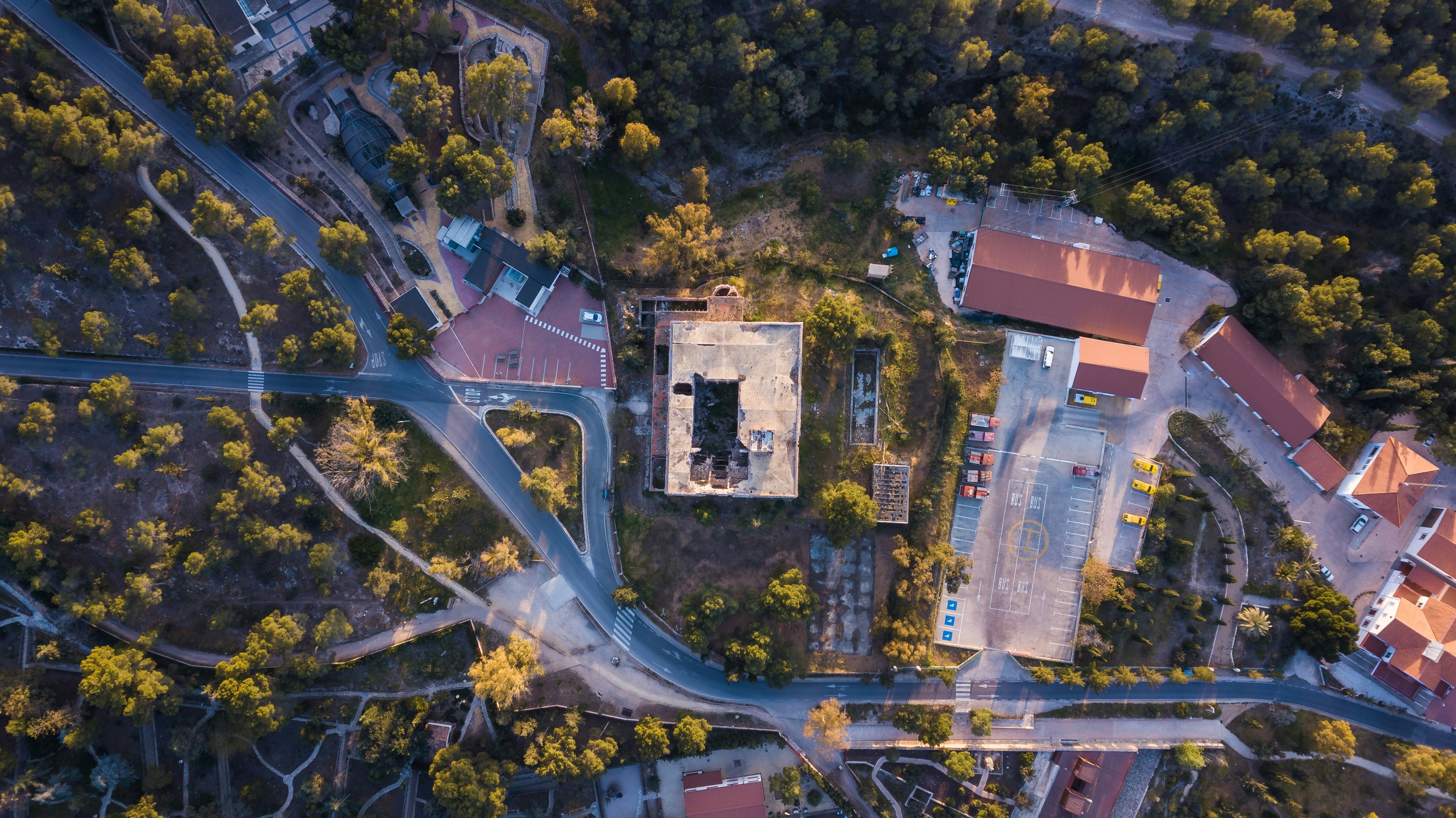 Aerial view of a complex with buildings and roads surrounded by dense trees.