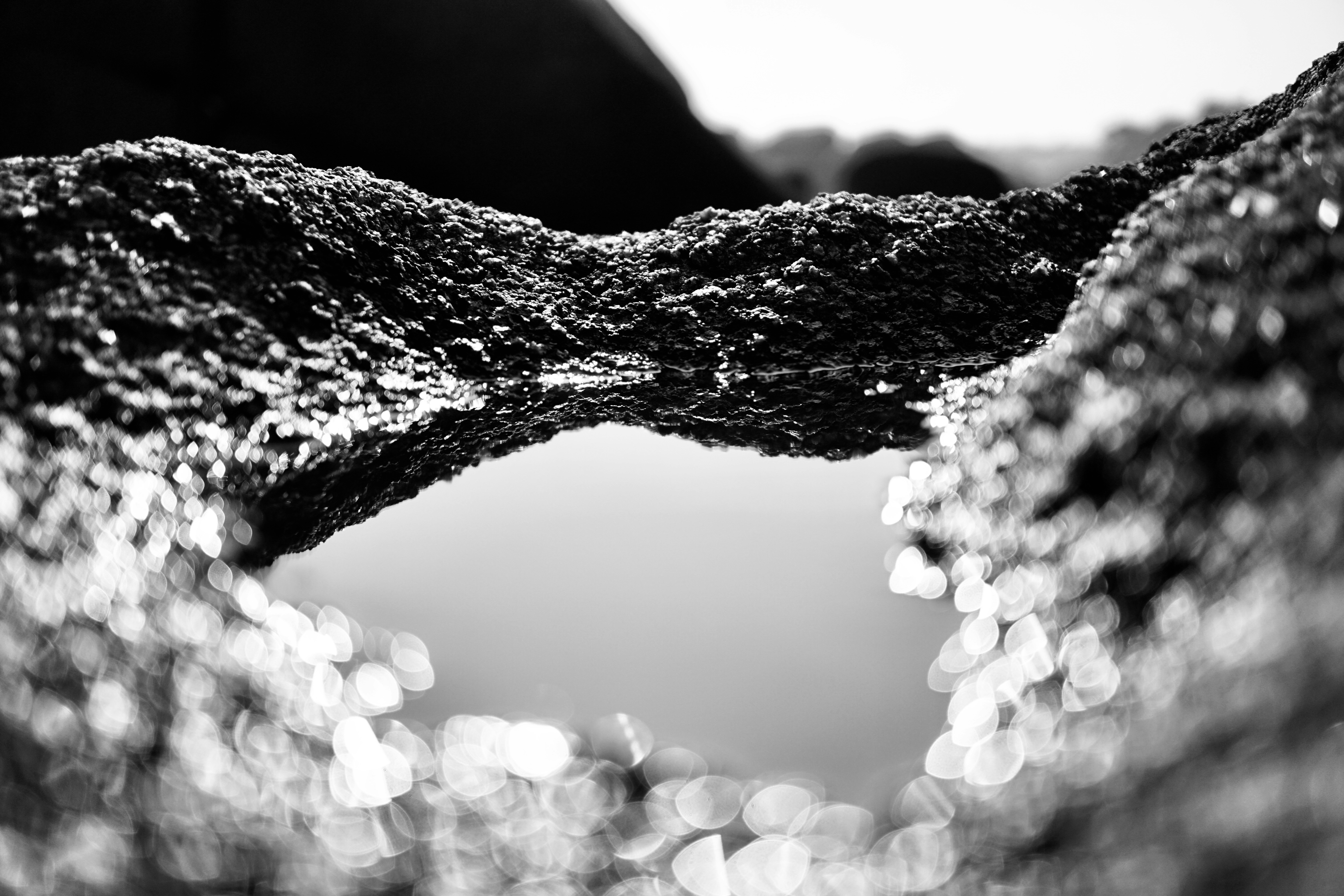 Close-up of water reflecting light through a textured rock formation in black and white.