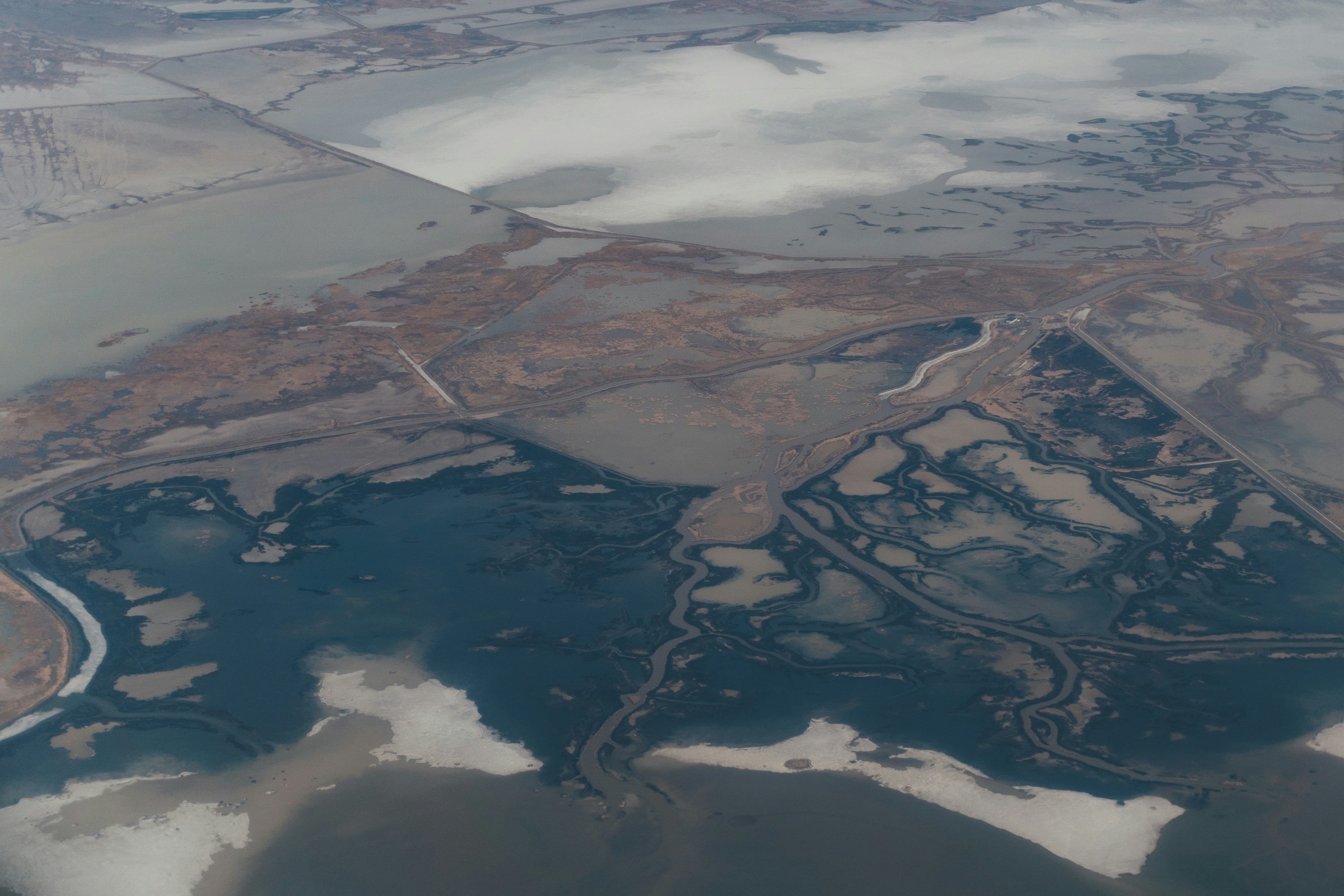 Intricate patterns of water and land create a striking aerial view of coastal wetlands, showcasing the interplay of nature's textures and colors.