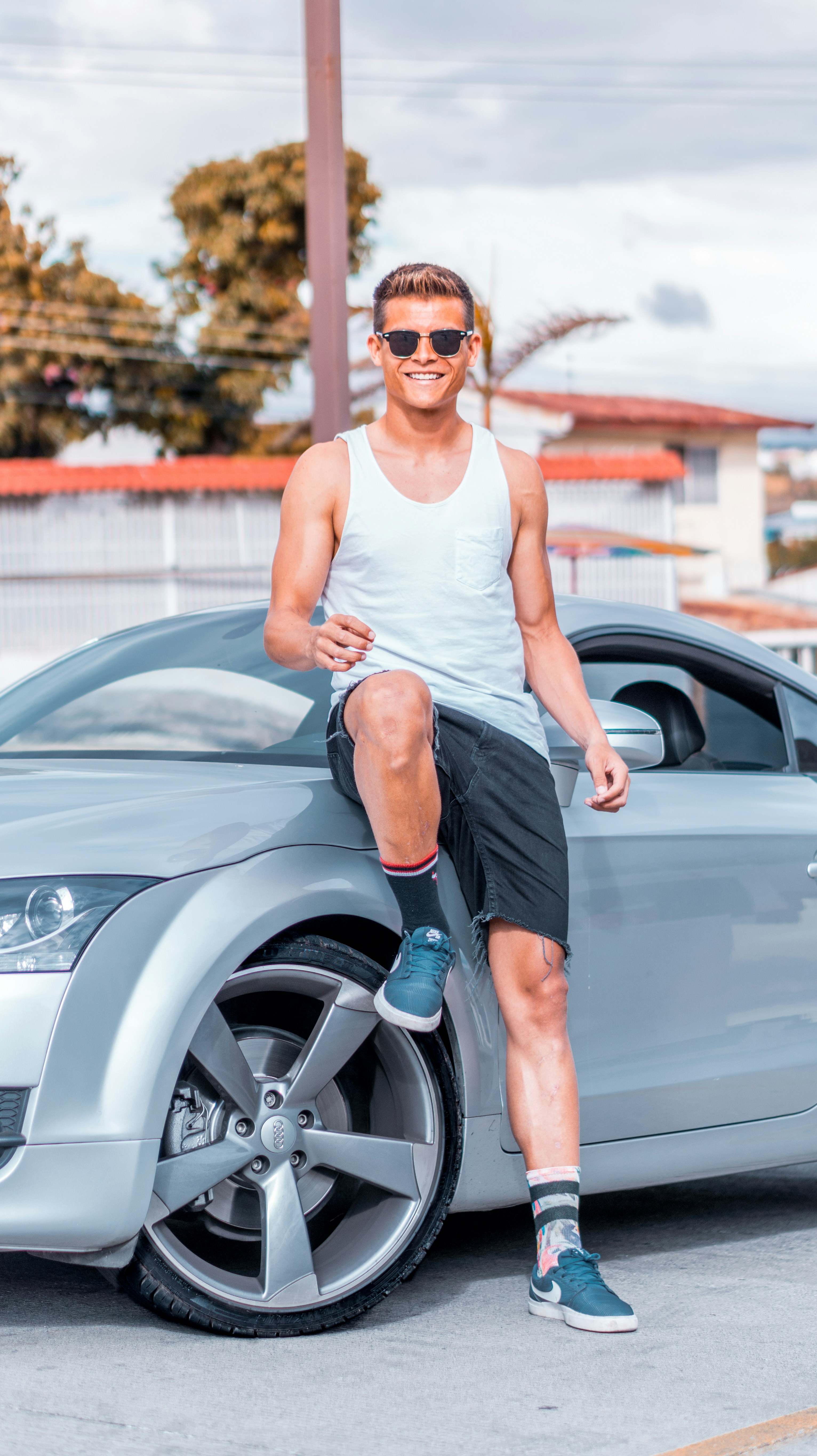 Sunlit Stance on Chrome Curves: A Casual Portrait by a Silver Sports Car
