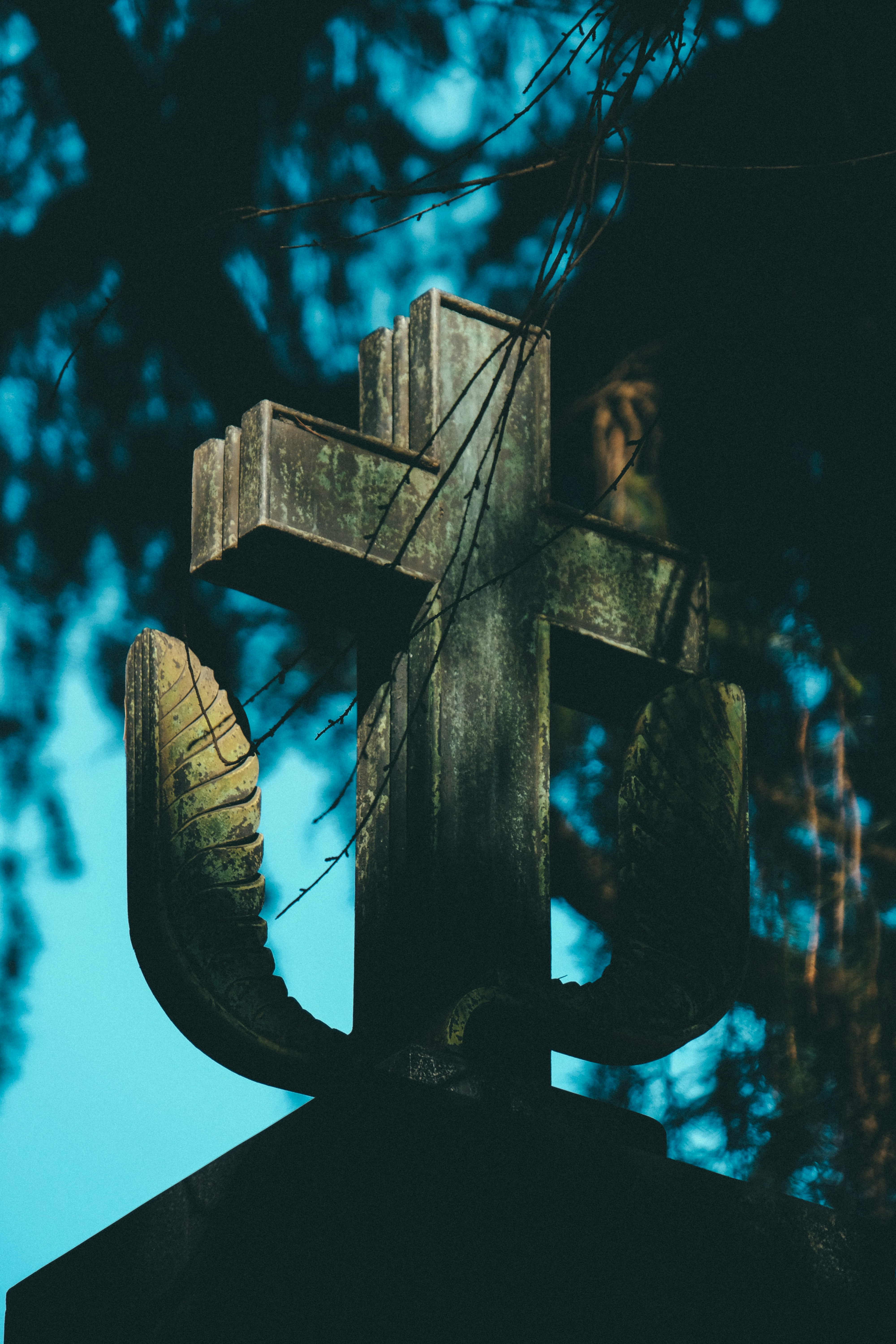 Patinaed Crosshead Framed by Barbed Wire Against an Azure Sky