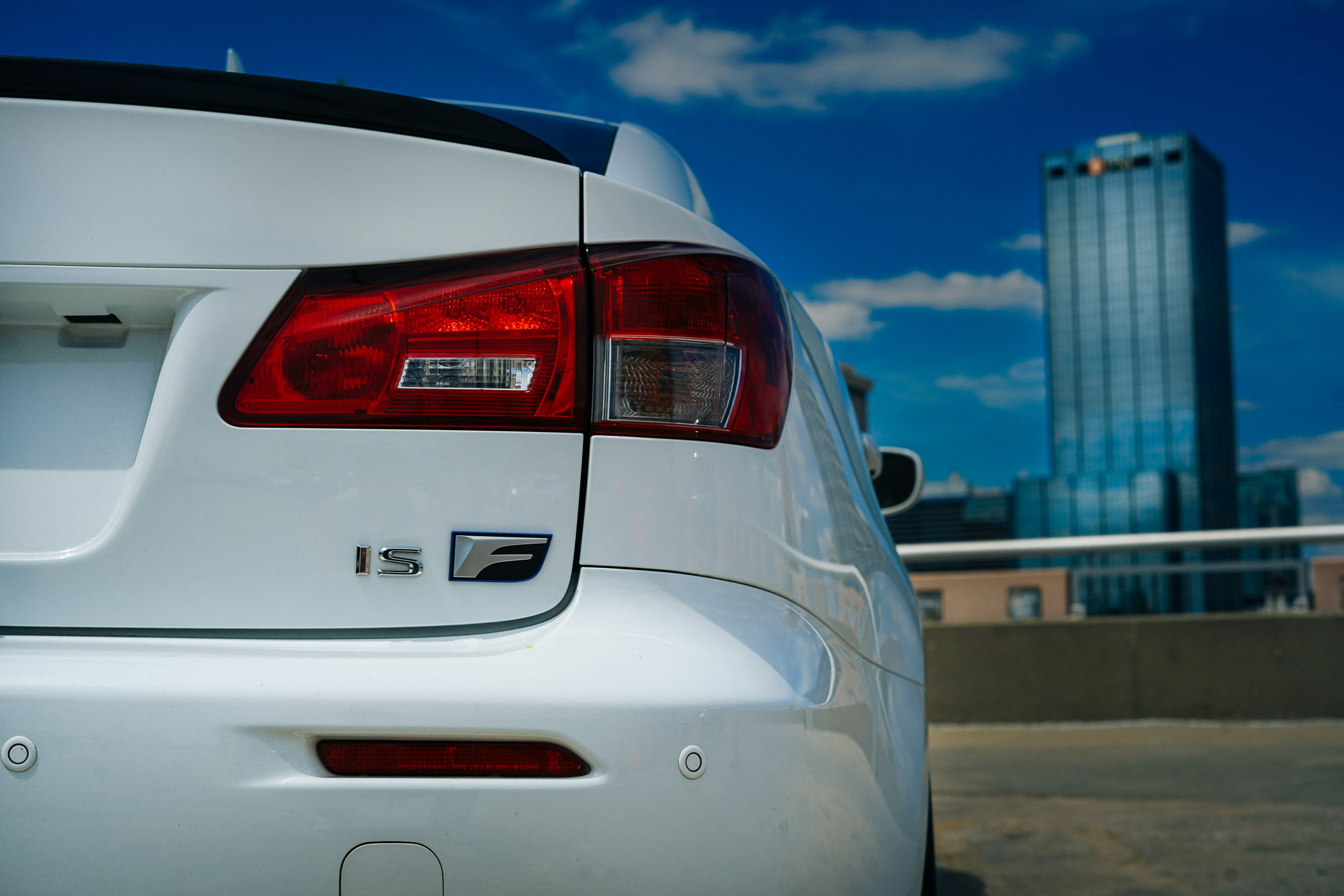 Lexus IS F: taillight focus against a distant city skyline