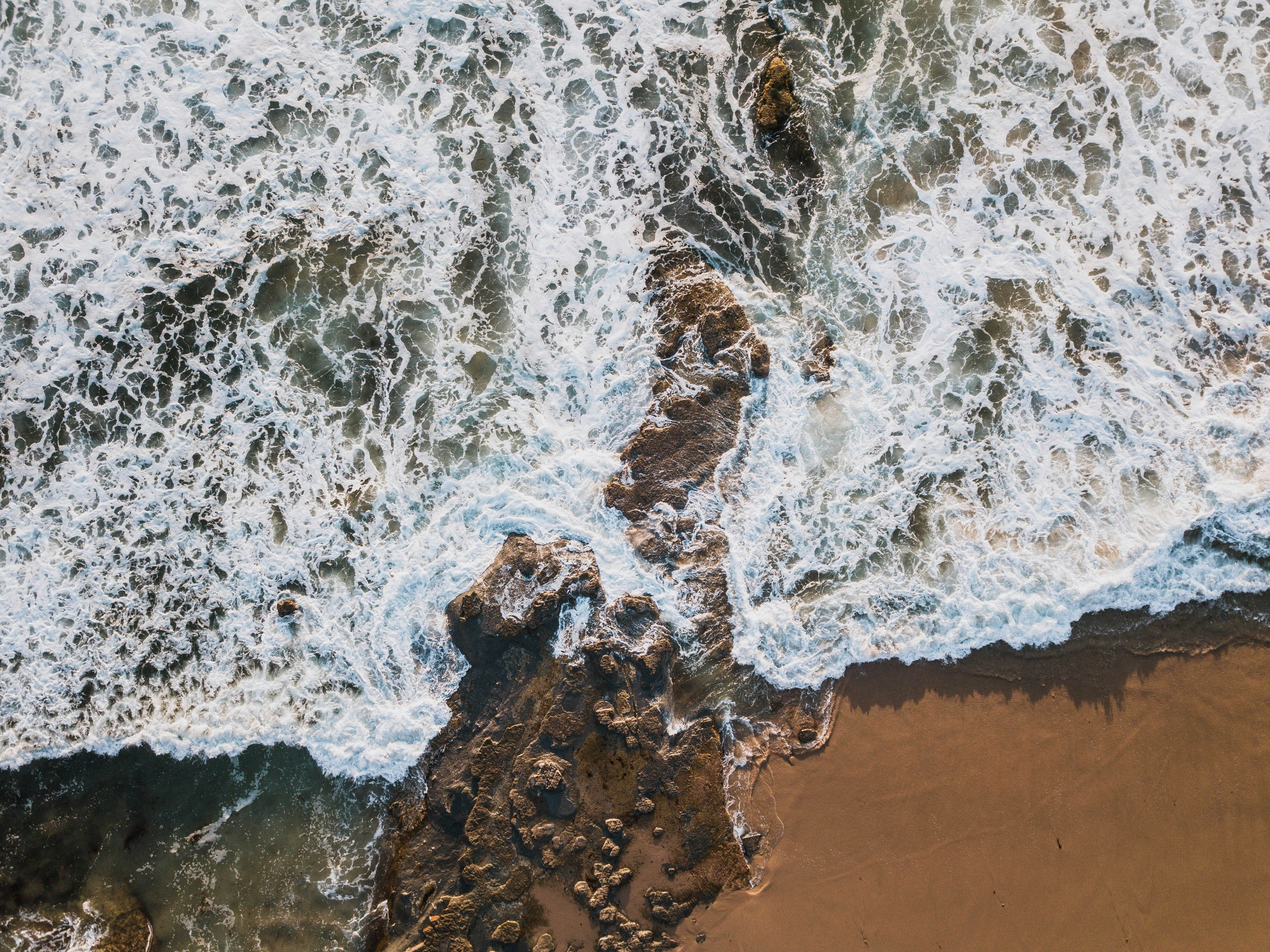 Water hitting rocks on shore during daytime photo – Free Grey Image on ...