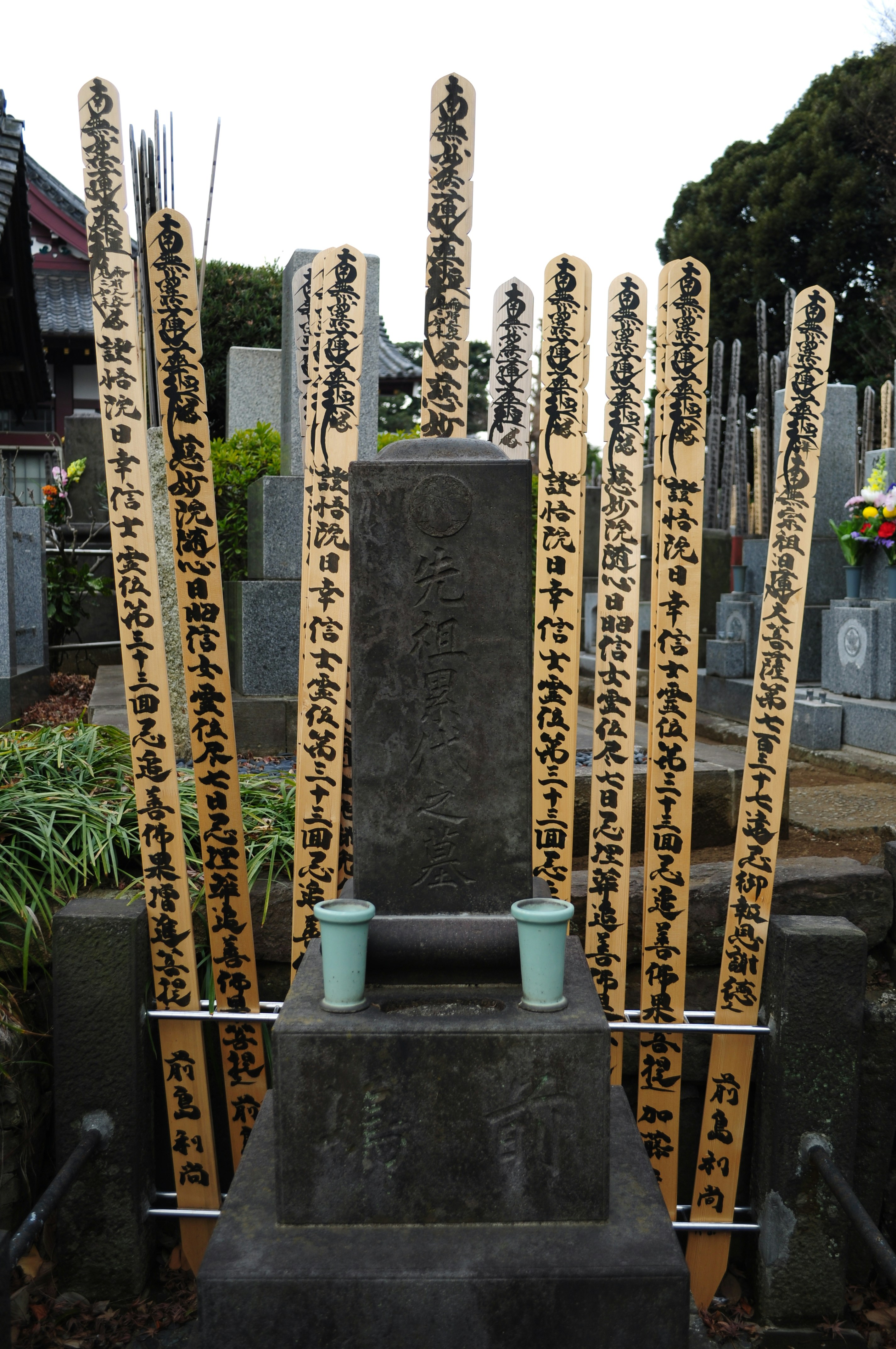 A solemn grave site adorned with wooden memorial tablets and a stone monument, reflecting cultural reverence and remembrance.