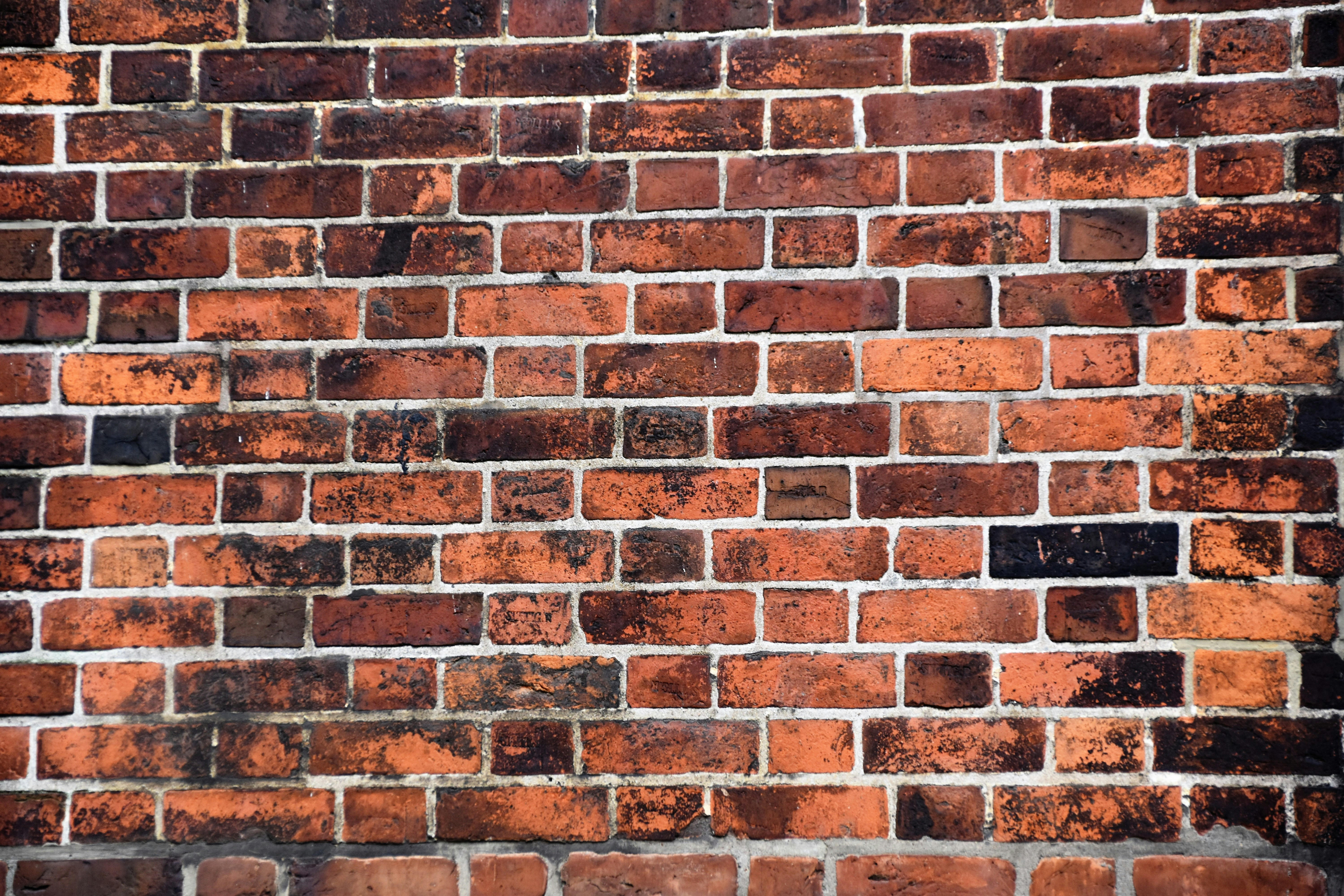 Textured red brick wall showcasing a blend of colors and patterns, highlighting the passage of time and craftsmanship.