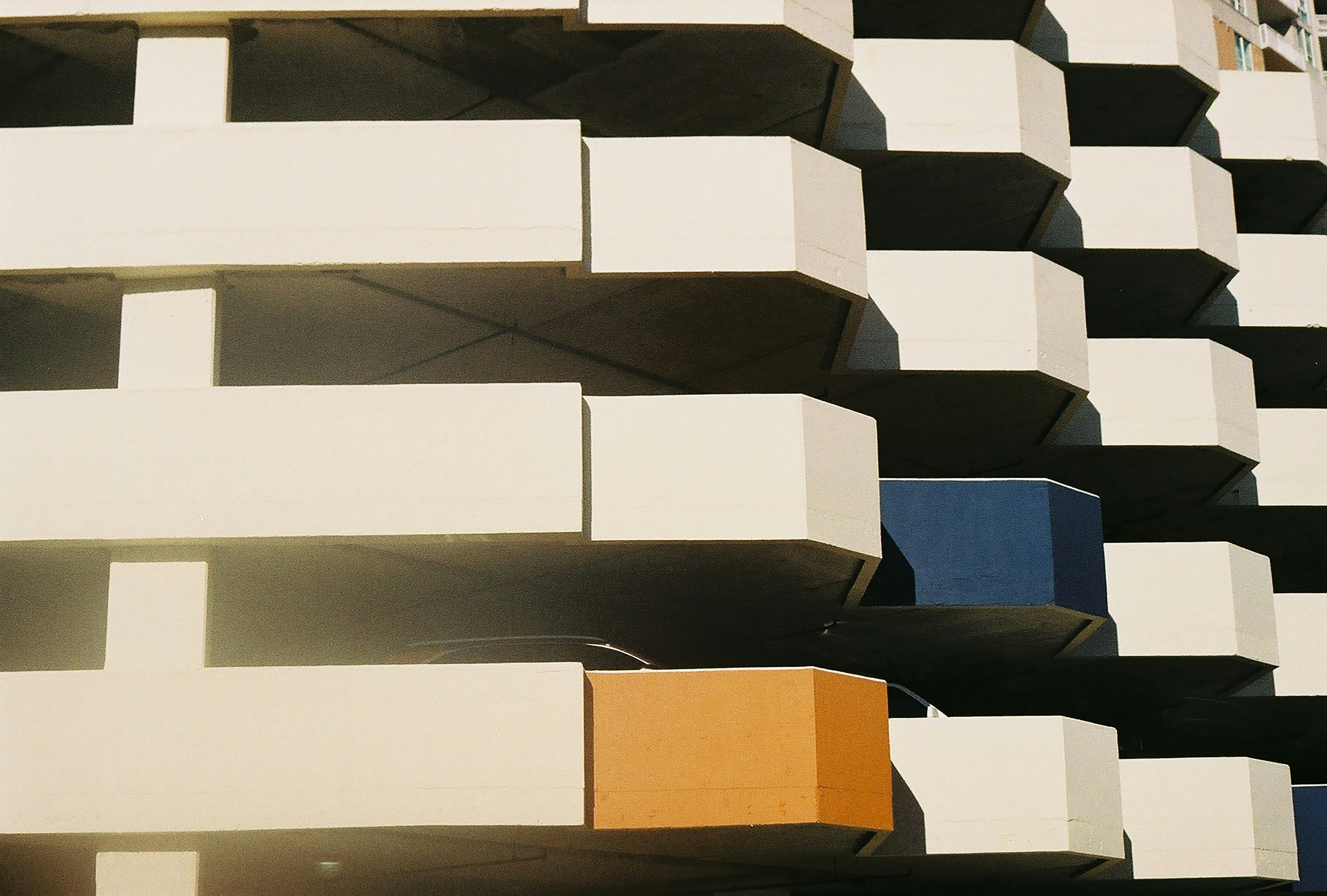 Abstract architectural detail showcasing layered concrete forms with vibrant color accents. The interplay of shadows and shapes creates a dynamic visual experience.