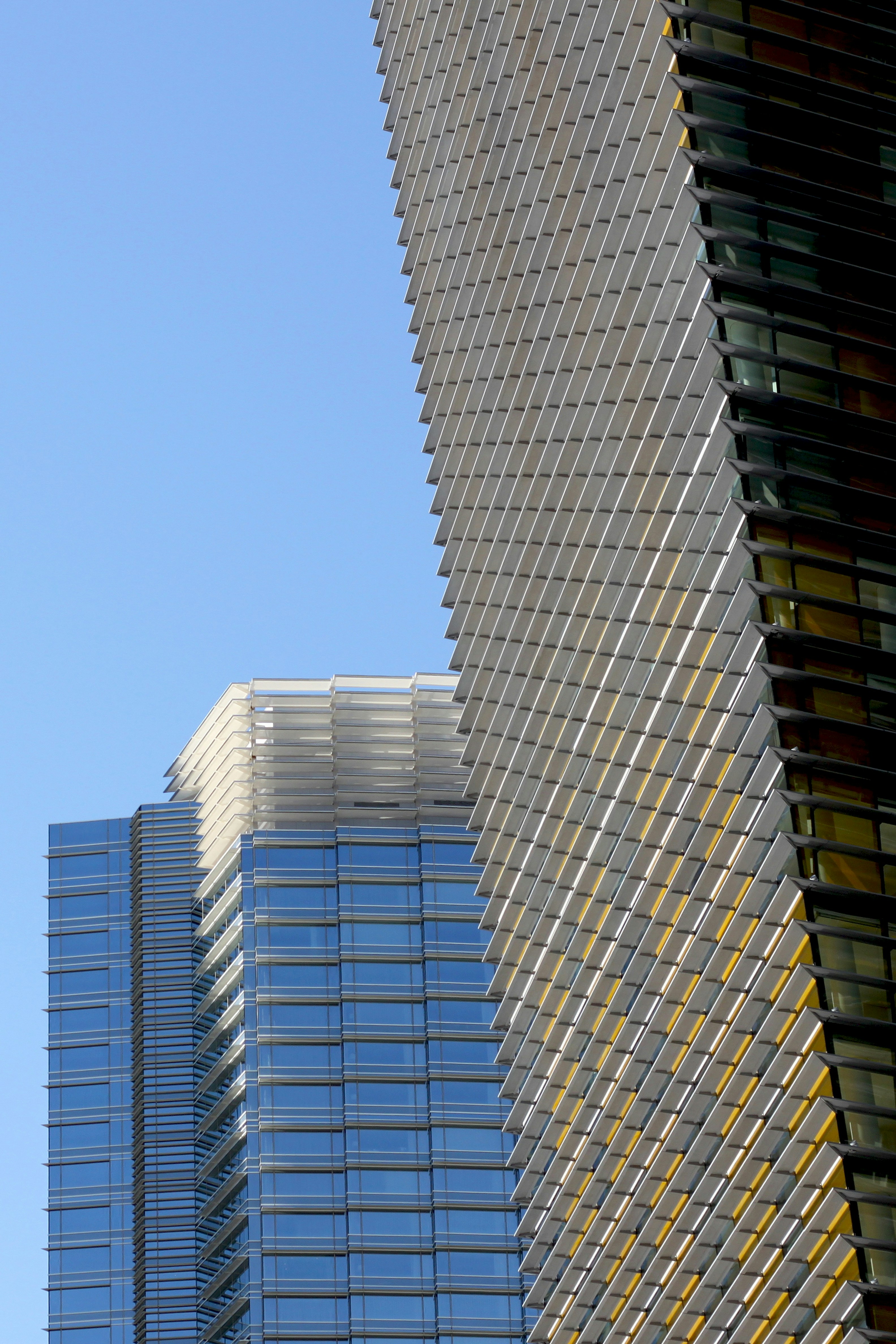 Architectural details of modern skyscrapers showcasing reflective glass and angular designs against a clear sky.