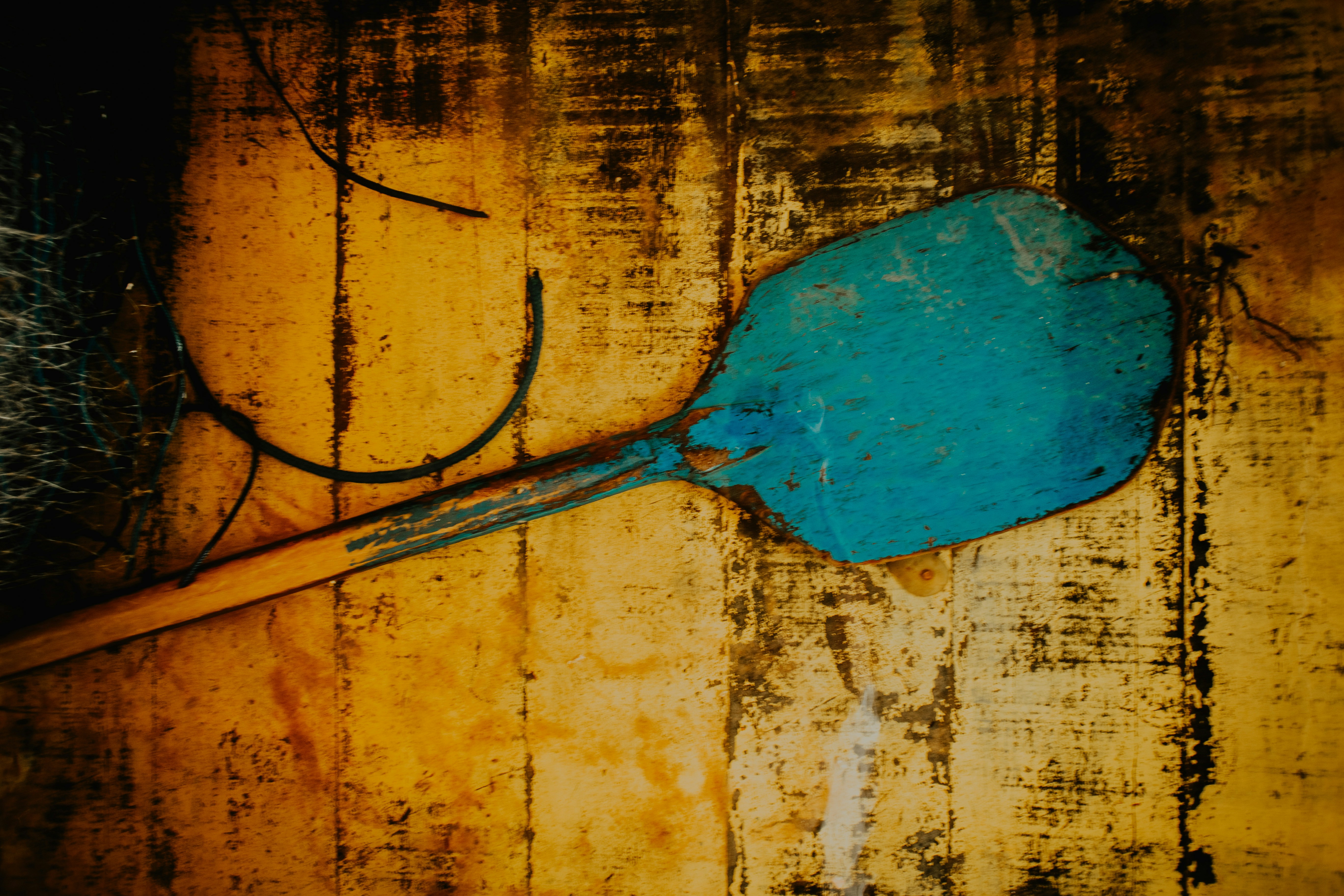 Blue spatula blade under warm weathered paint—a still life of color and texture