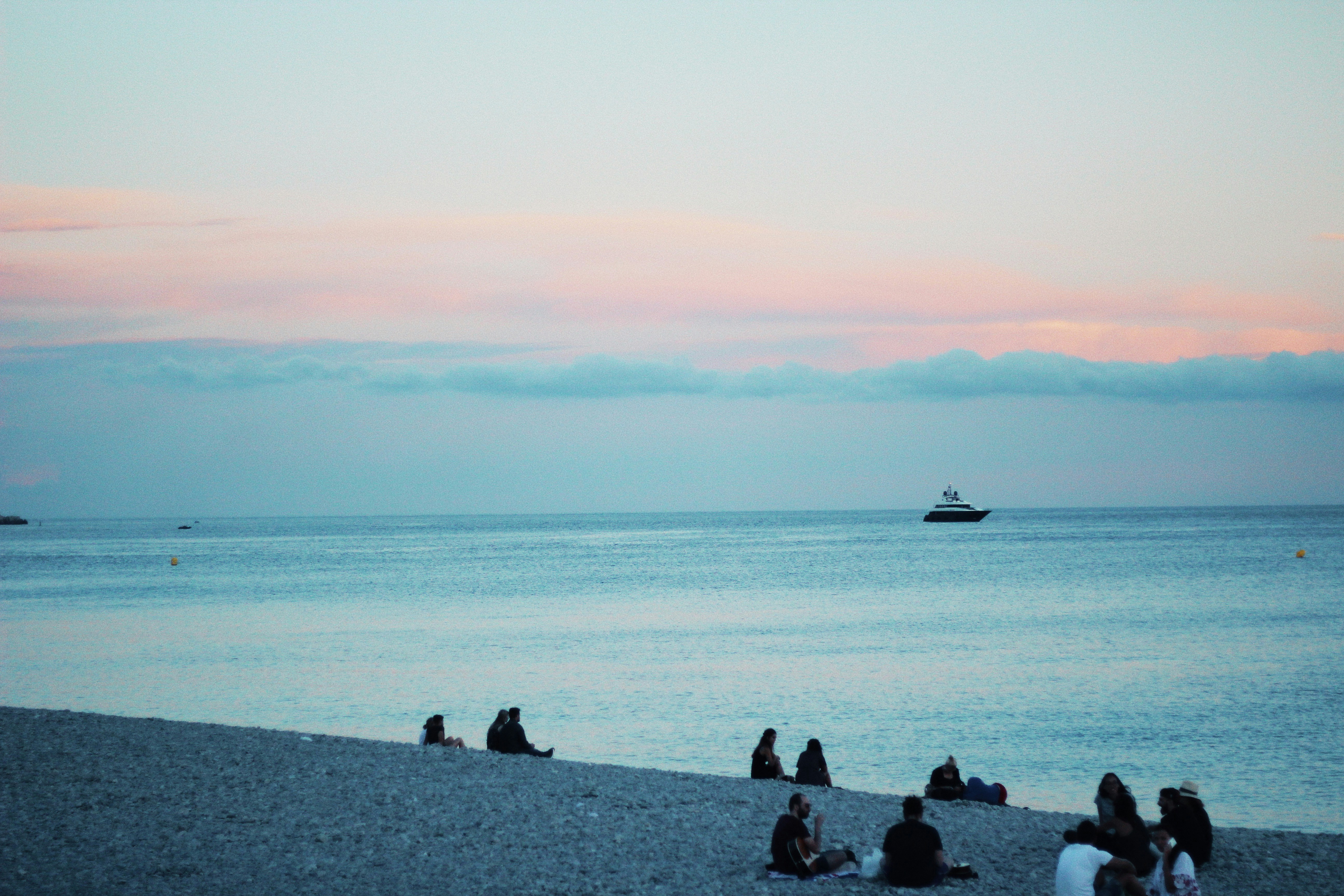 Horizon Vessel at Dusk: Silhouettes on a Pebble Beach
