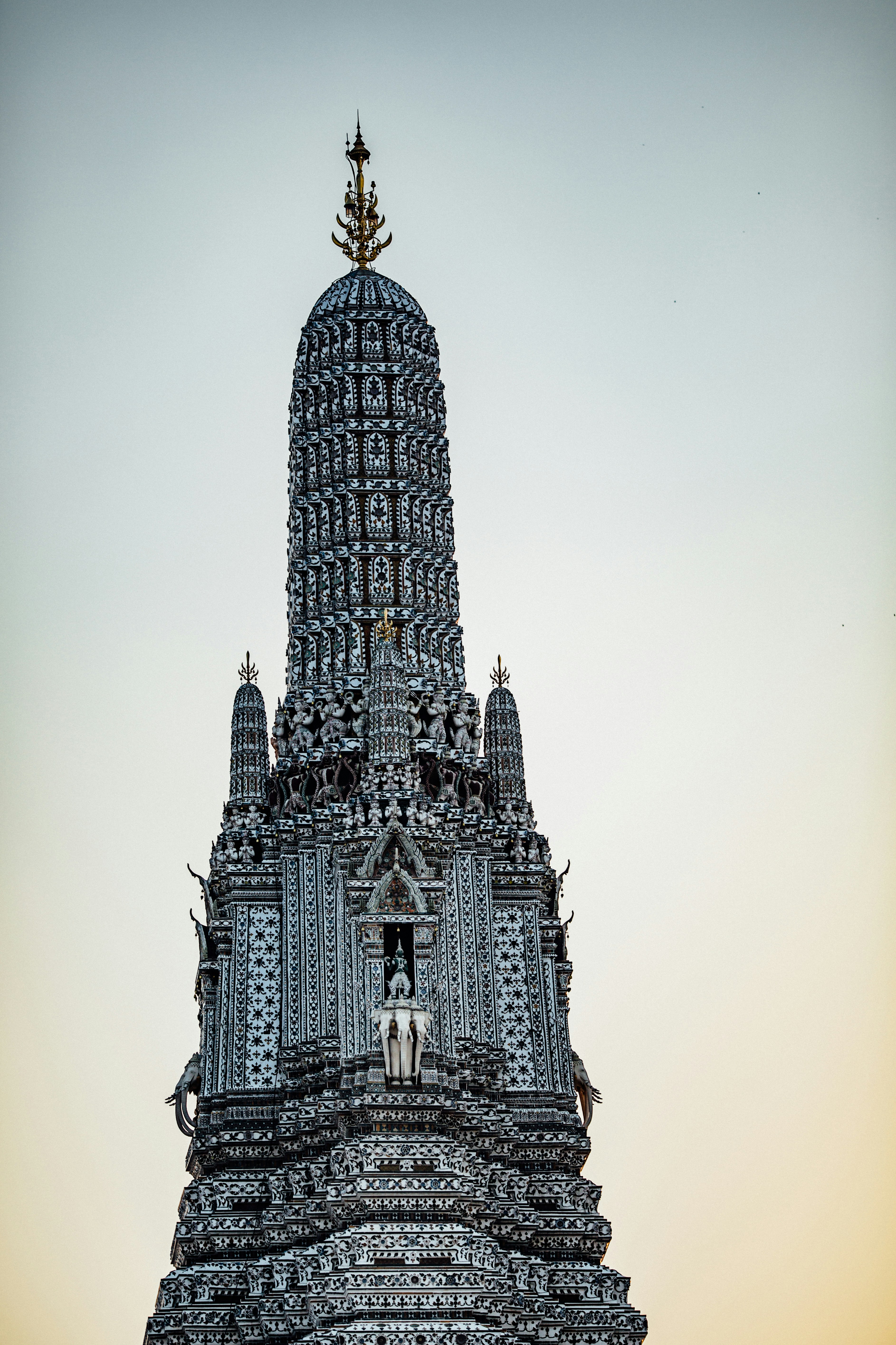 Intricate temple tower adorned with detailed sculptures and decorative elements against a soft gradient sky.