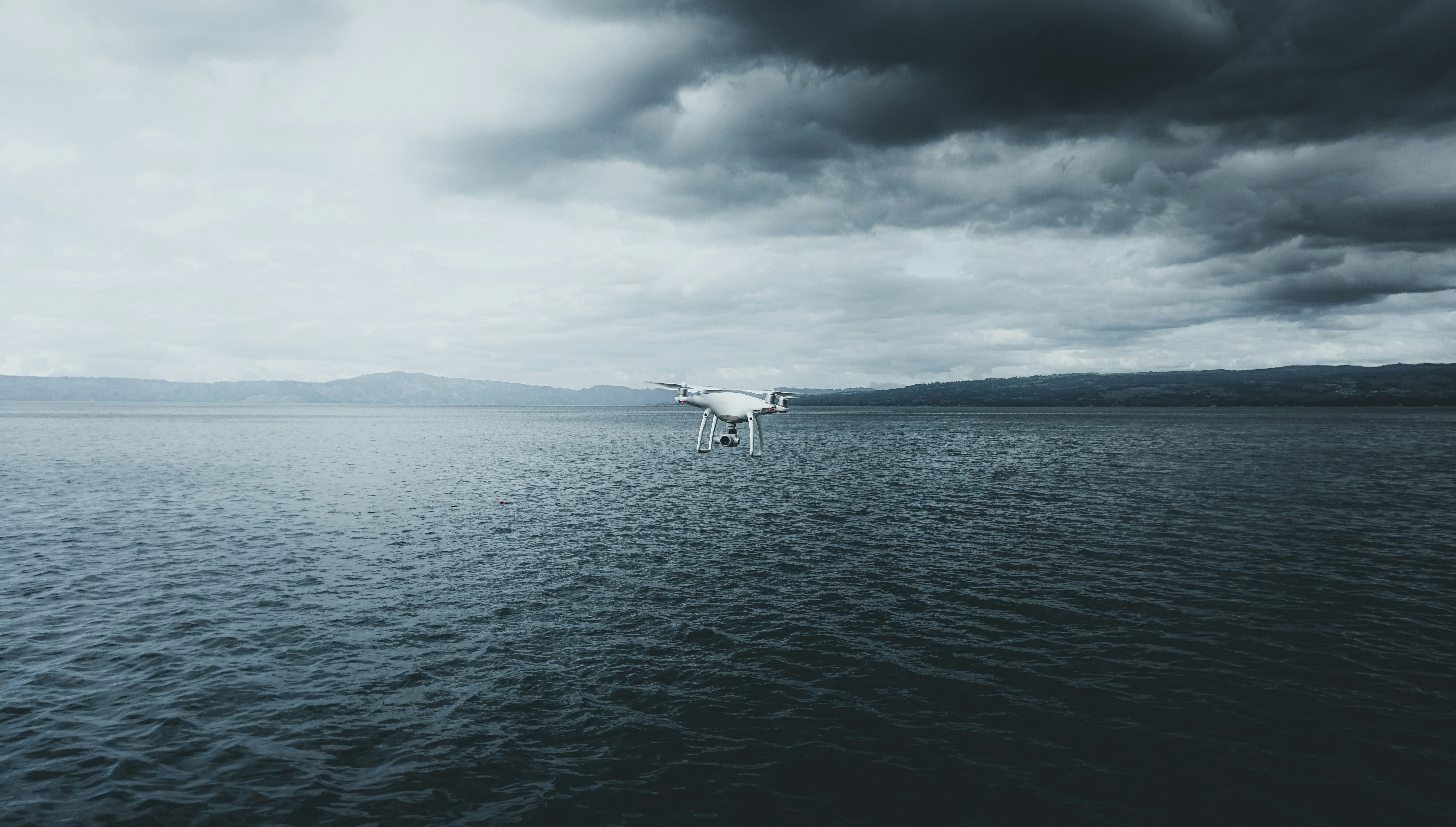 Boat on a vast, dark ocean beneath dramatic, overcast clouds.