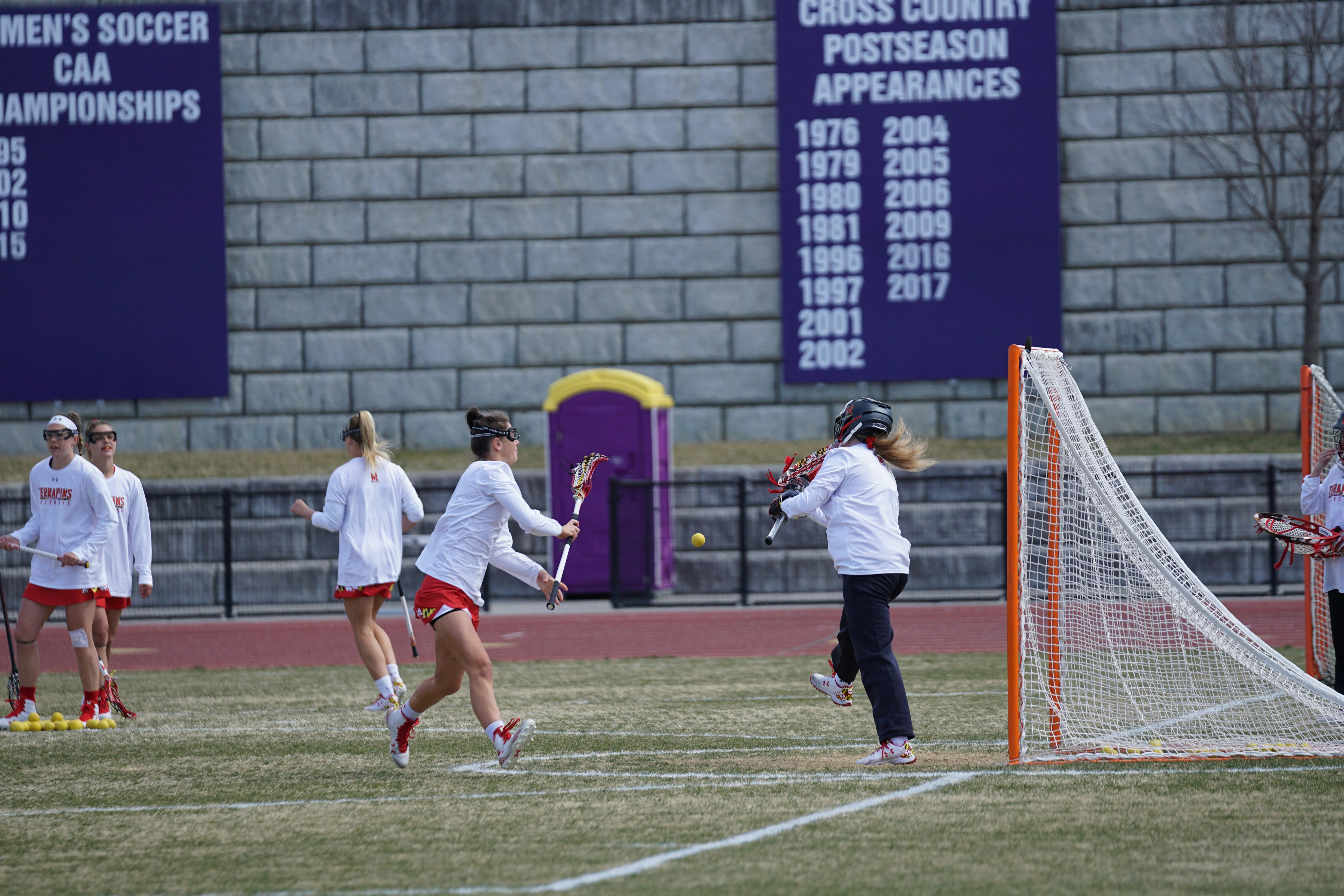 Jump for the Save: A Lacrosse Drill Under Purple Stadium Banners