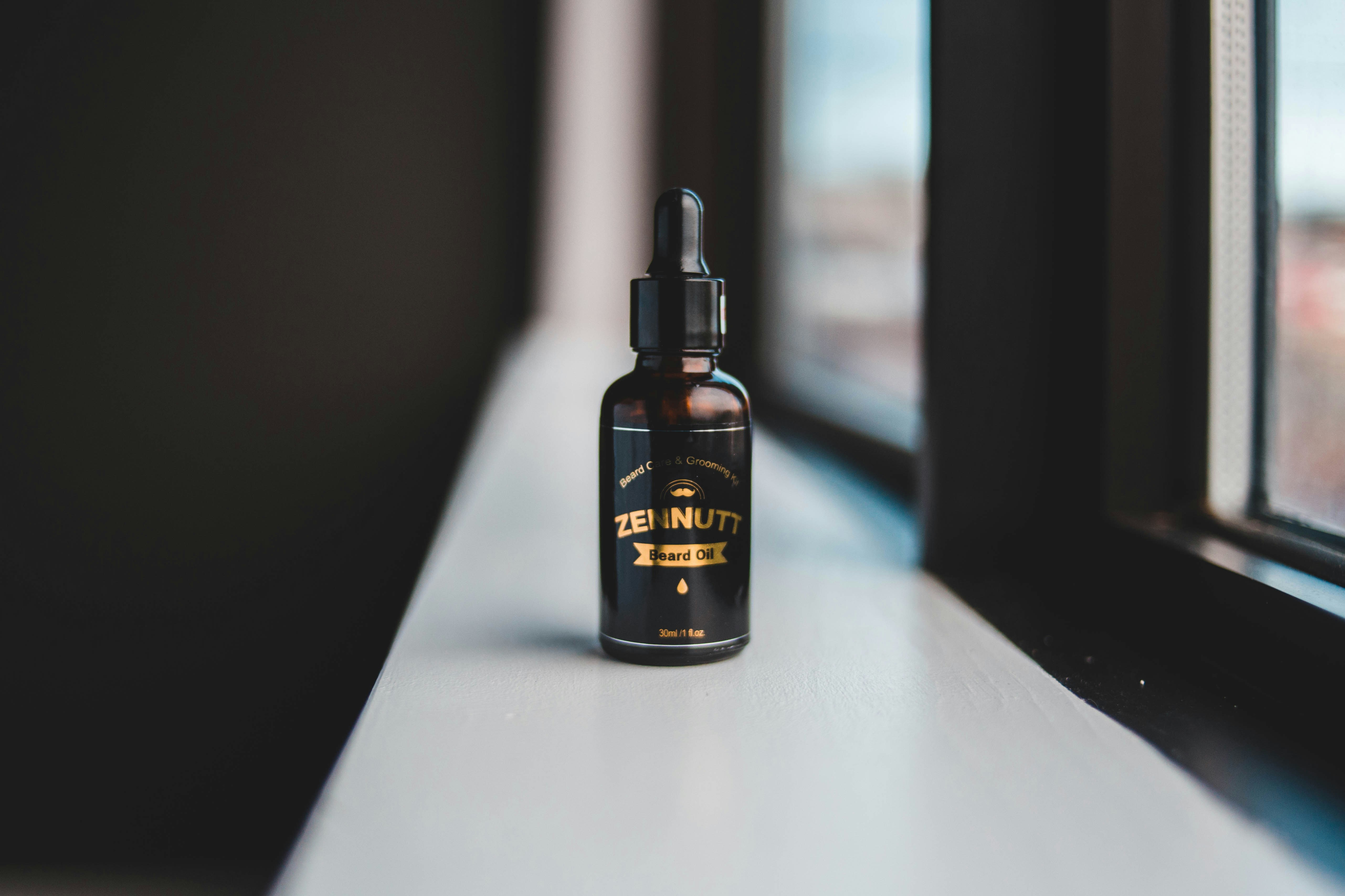 Black and gold-labeled dropper bottle placed near window photo – Free ...