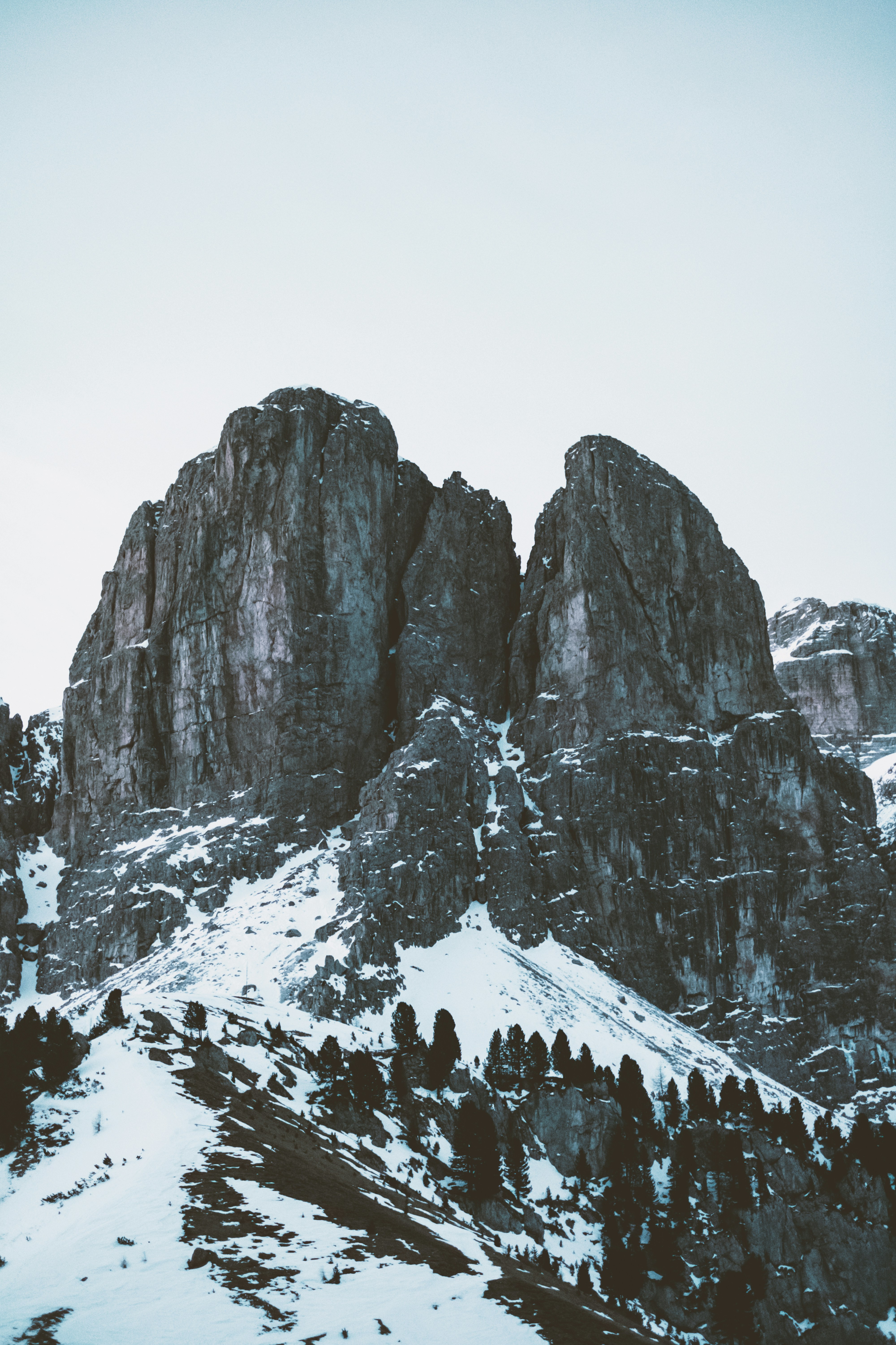 Snow-dusted Brunecker Turm in the Dolomites rises sharply against a pastel sky.