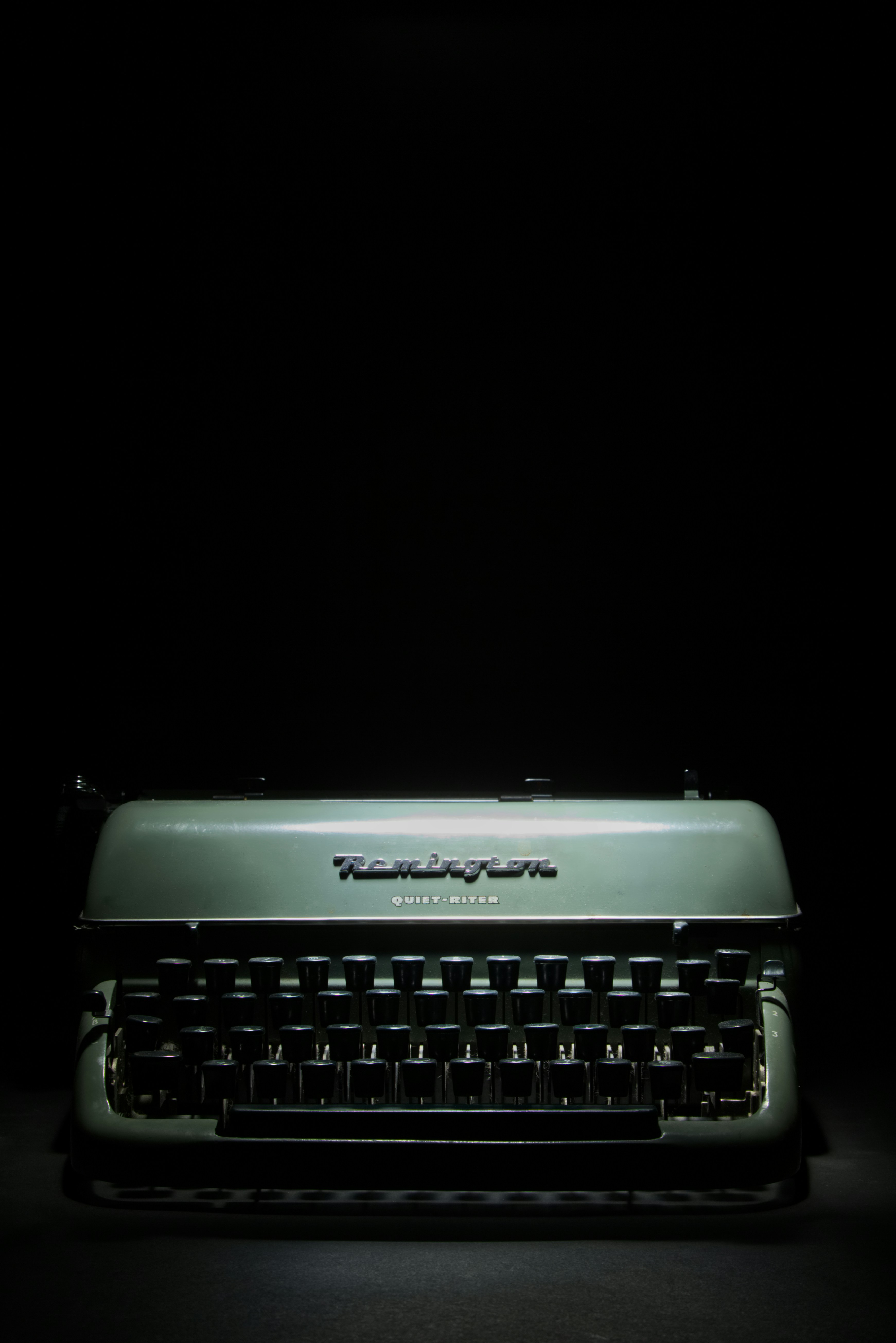 A vintage Remington typewriter illuminated against a dark backdrop, showcasing its elegant design and nostalgic charm.