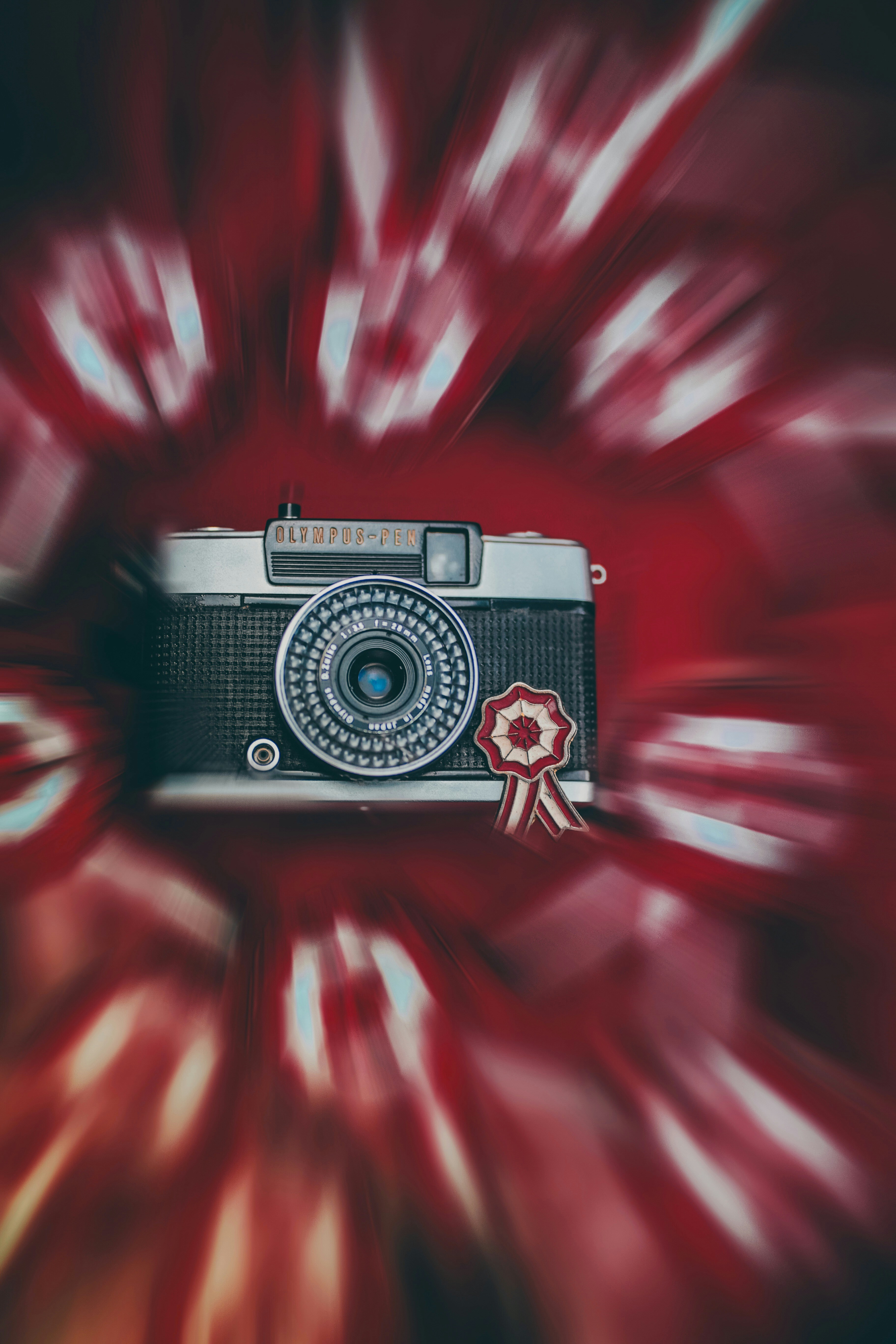 Legacy in Focus: A Vintage Olympus Camera Surrounded by Velvet Crimson Blur