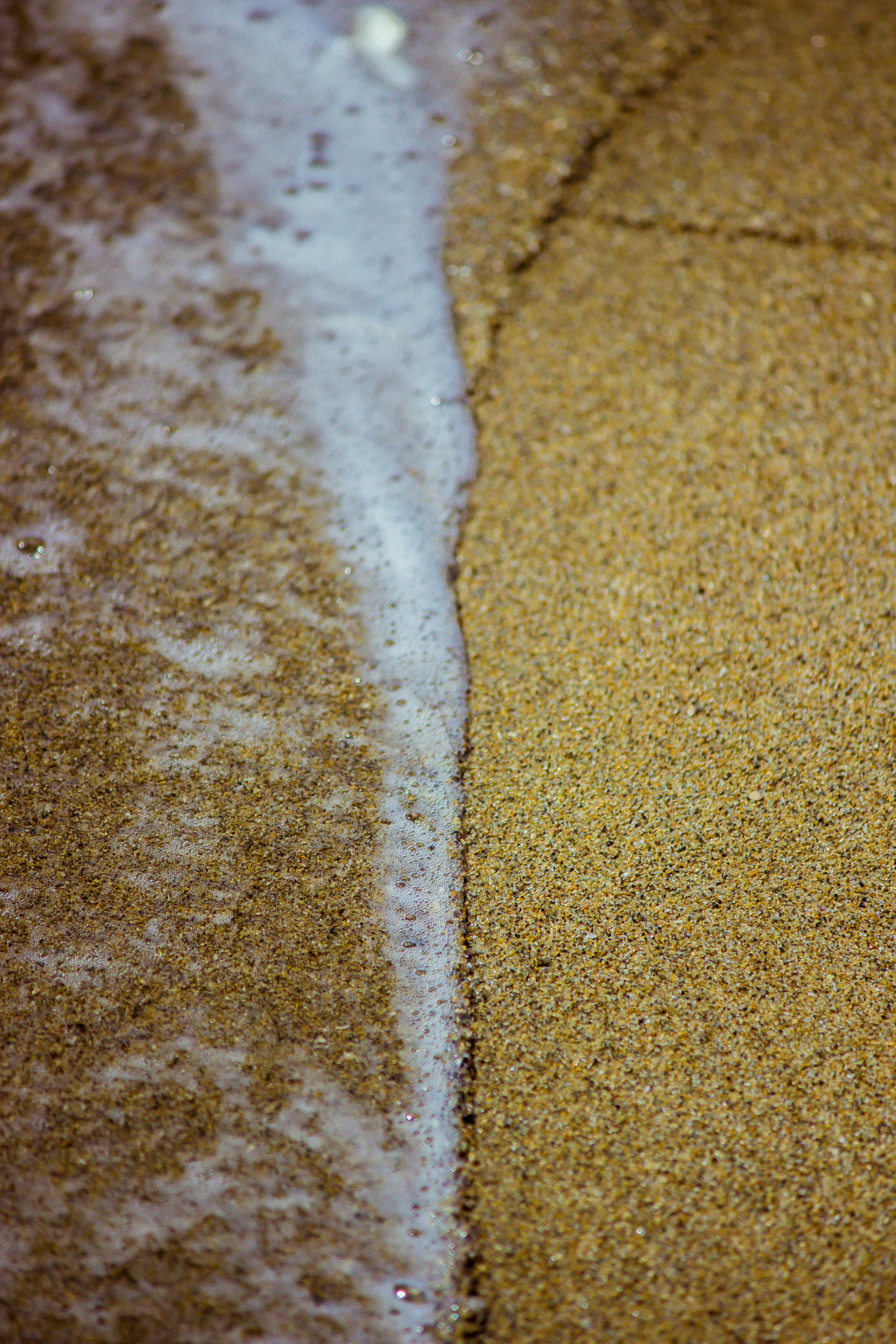Foamy waves caress the golden sand, creating a seamless blend of textures along the beach. The interplay of water and sand captures the essence of coastal tranquility.