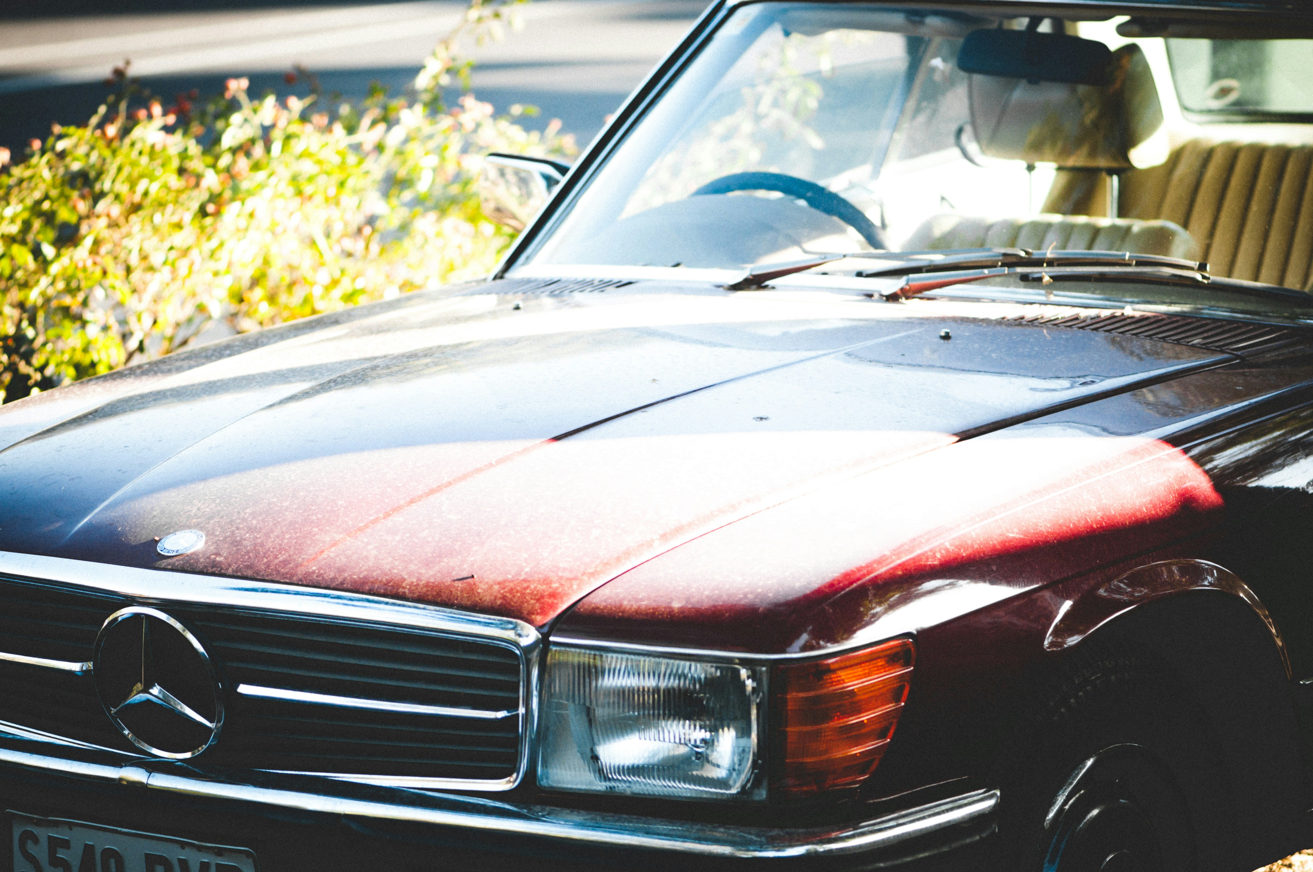 Sunlit chrome and burgundy hood: a vintage Mercedes captured in morning glow