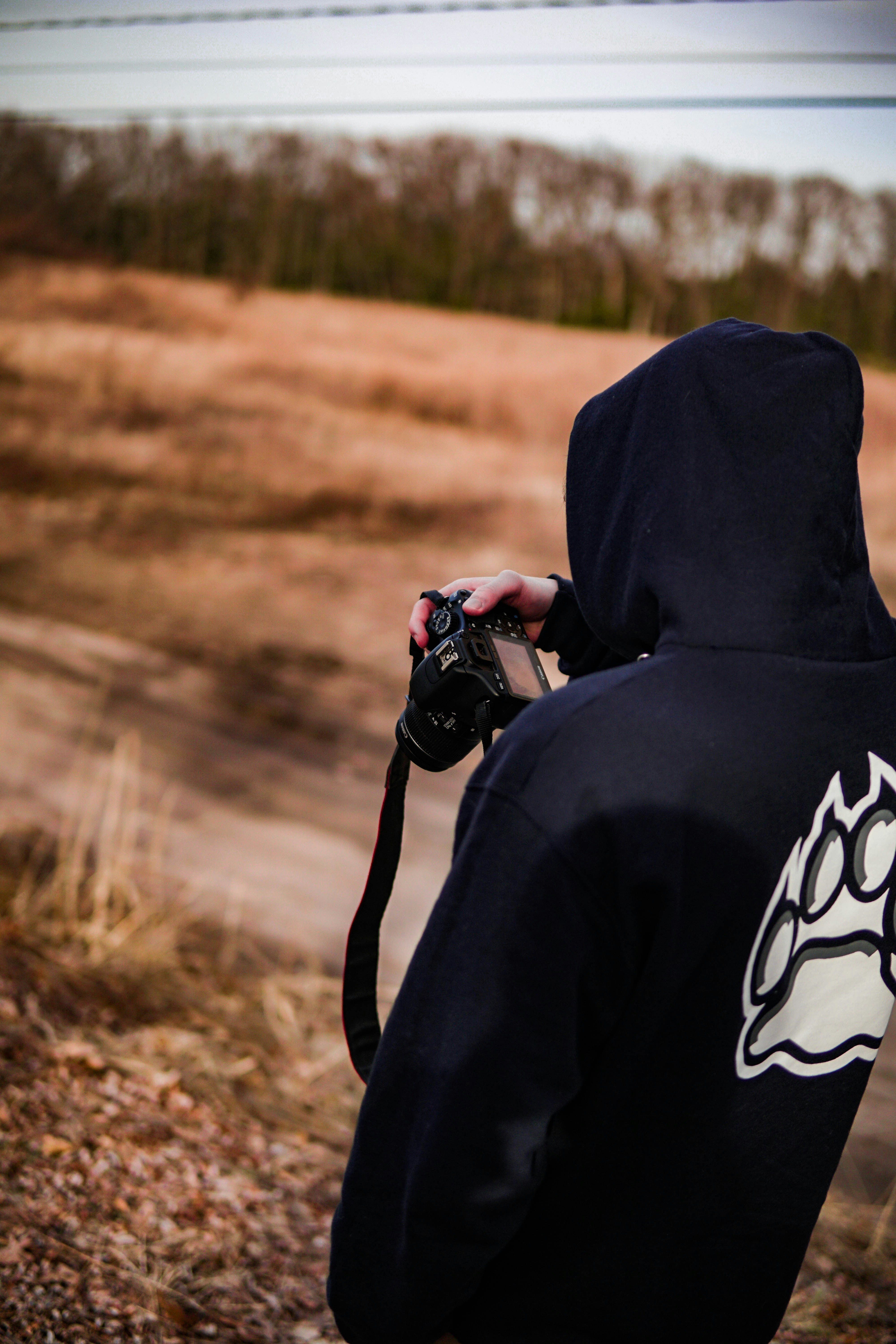 Hooded Photographer in a Dry Field Capturing the Moment