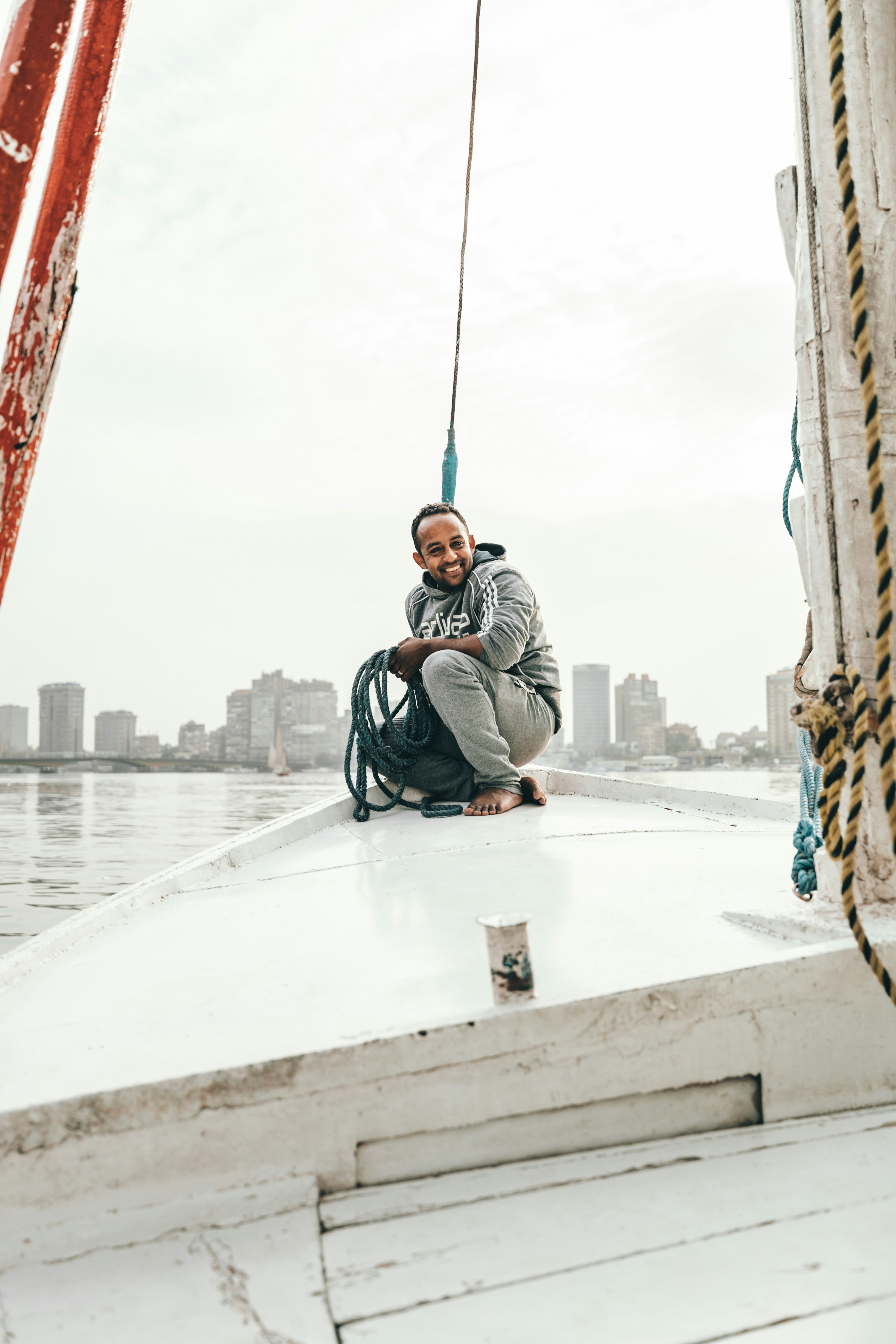 Bowline Moment: A Grinning Sailor on a White Boat with Urban Skyline