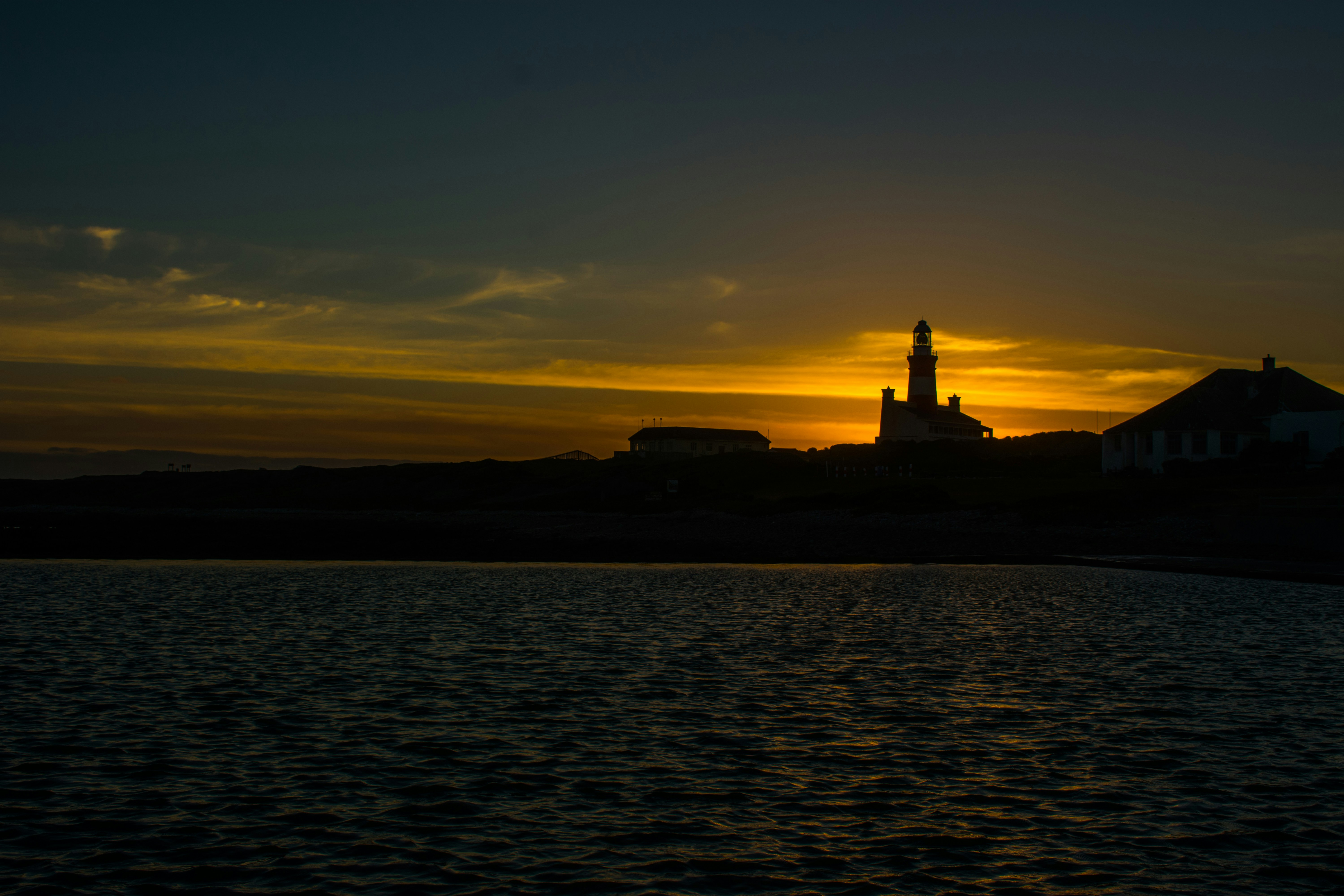 lighthouse tower on mountain near body of water