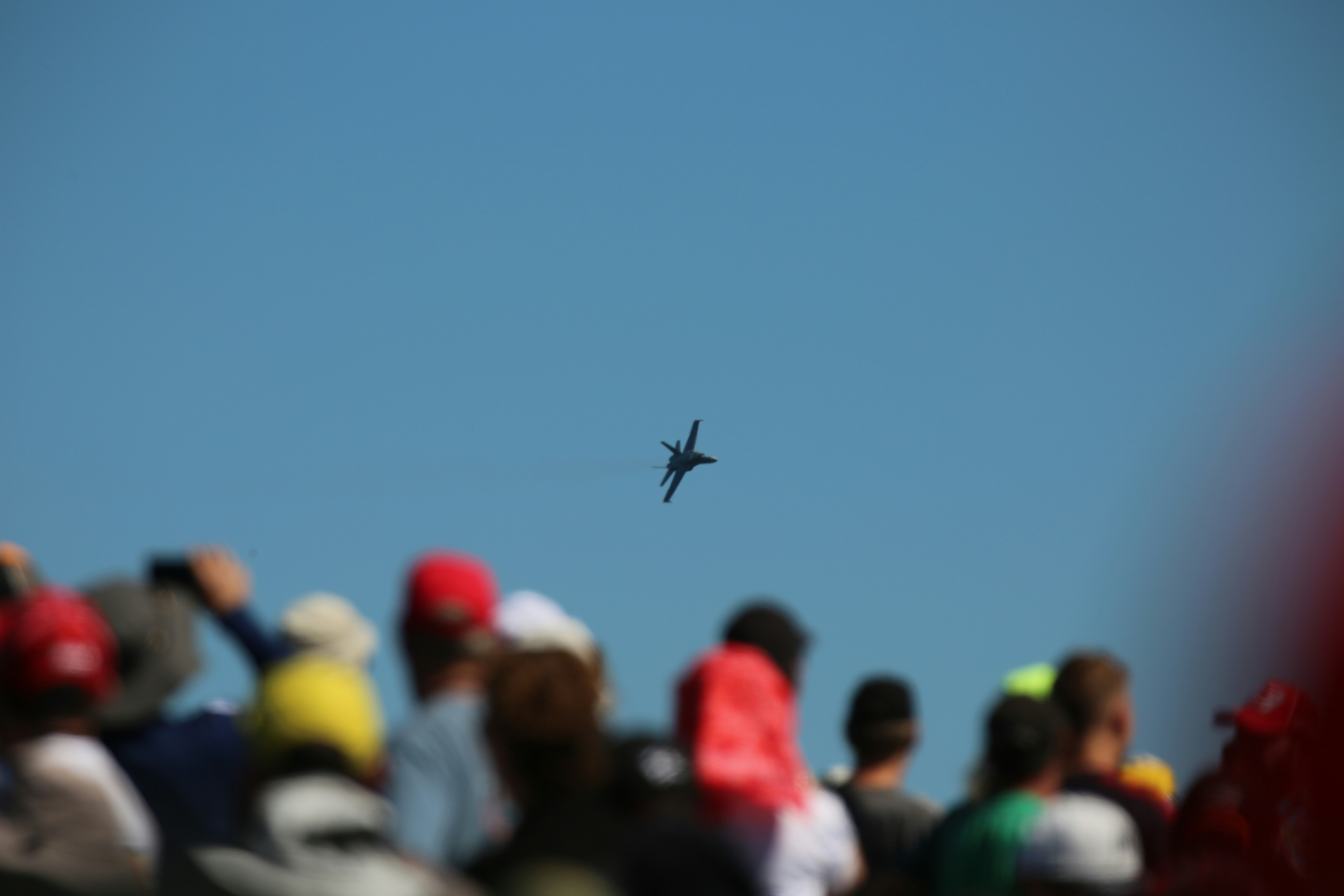 A crowd of people watching an airplane fly overhead photo – Free Blue ...