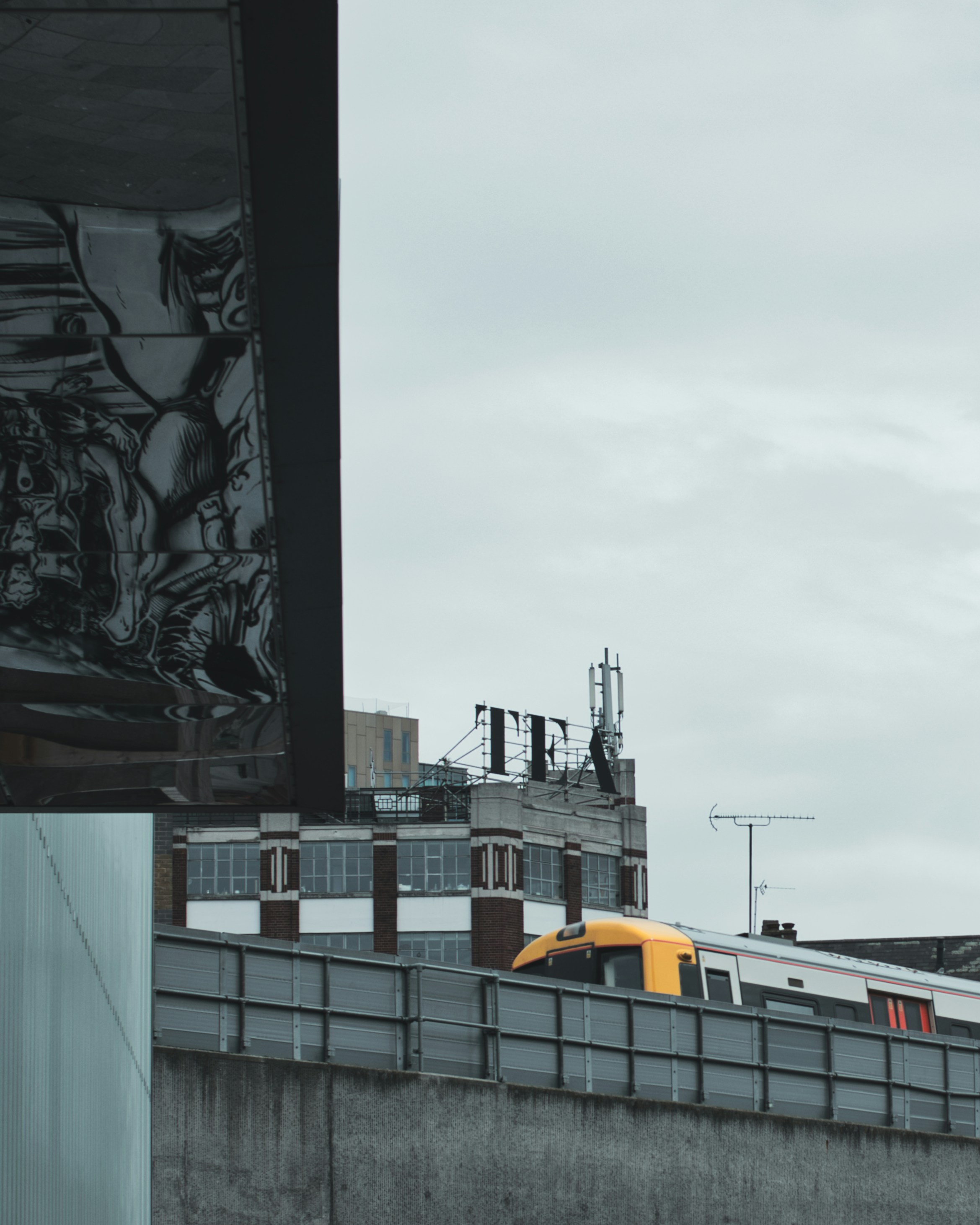 Orange Commuter on a Narrow City Overpass