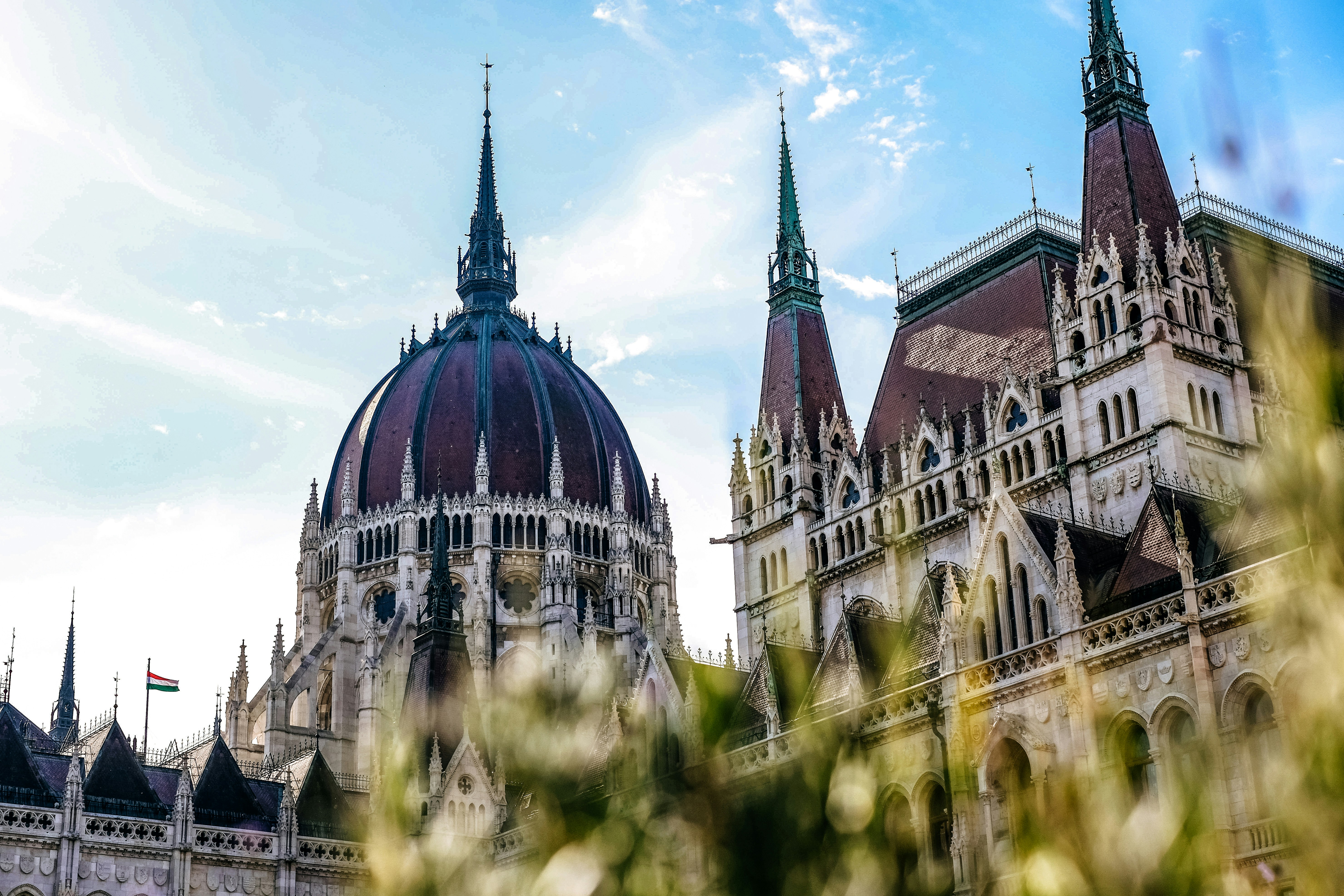Ornate Gothic architecture with a prominent dome and spires, set against a vibrant blue sky with wispy clouds.