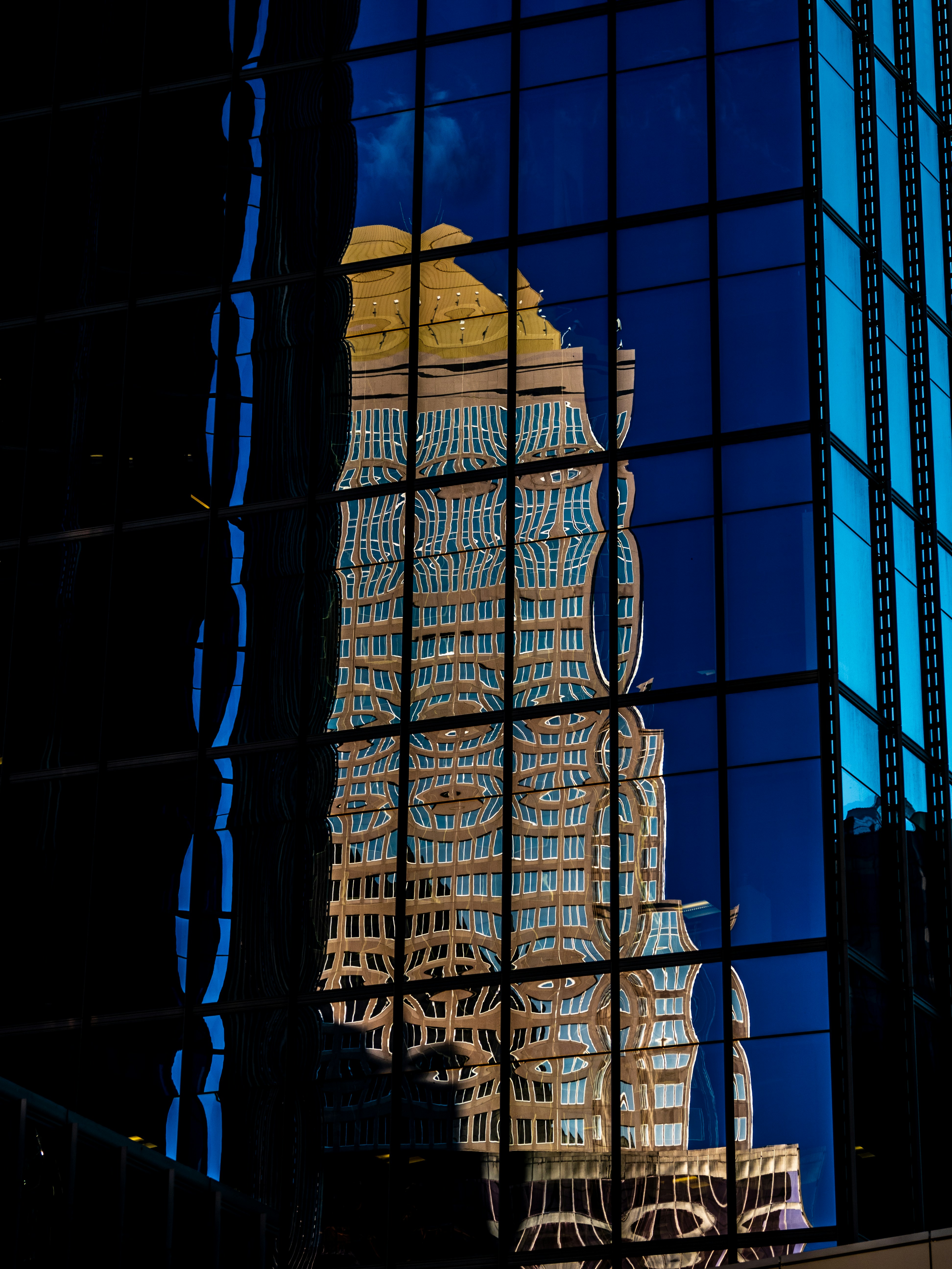 Grid Reflections: A Golden-Topped Tower Refracted Across a Glass Façade
