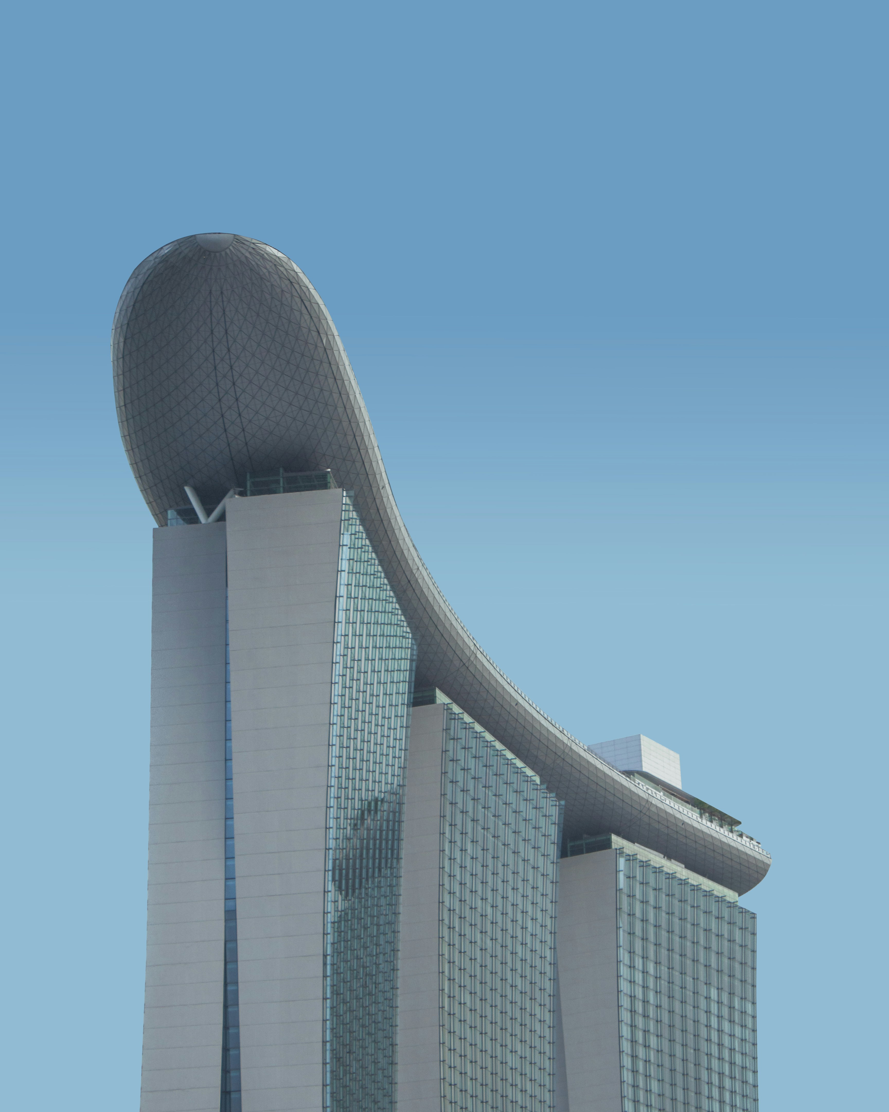Iconic skyscraper featuring a unique, curved rooftop design against a clear blue sky.