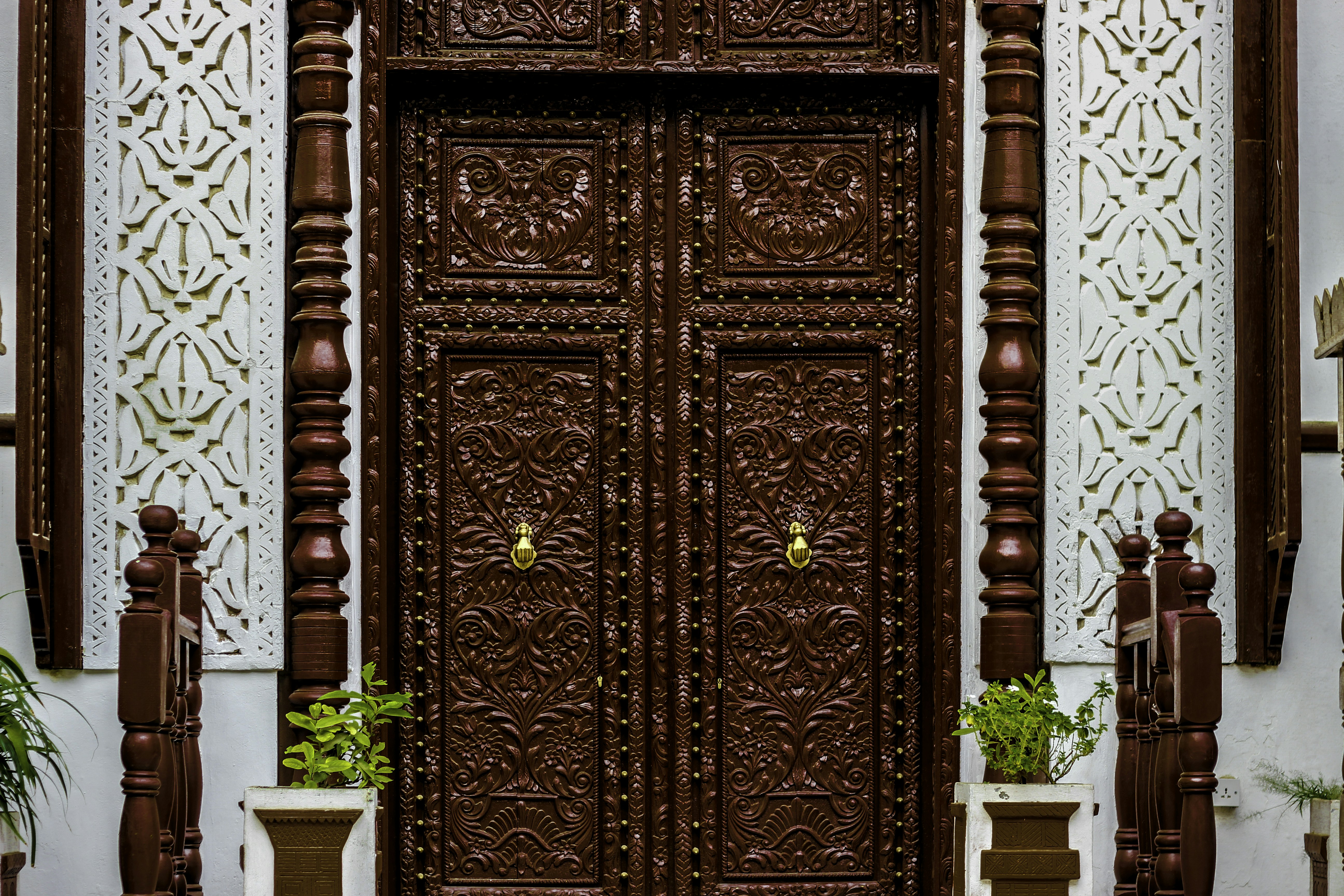 Elaborately carved wooden doors framed by intricately patterned walls, showcasing a blend of craftsmanship and cultural heritage.