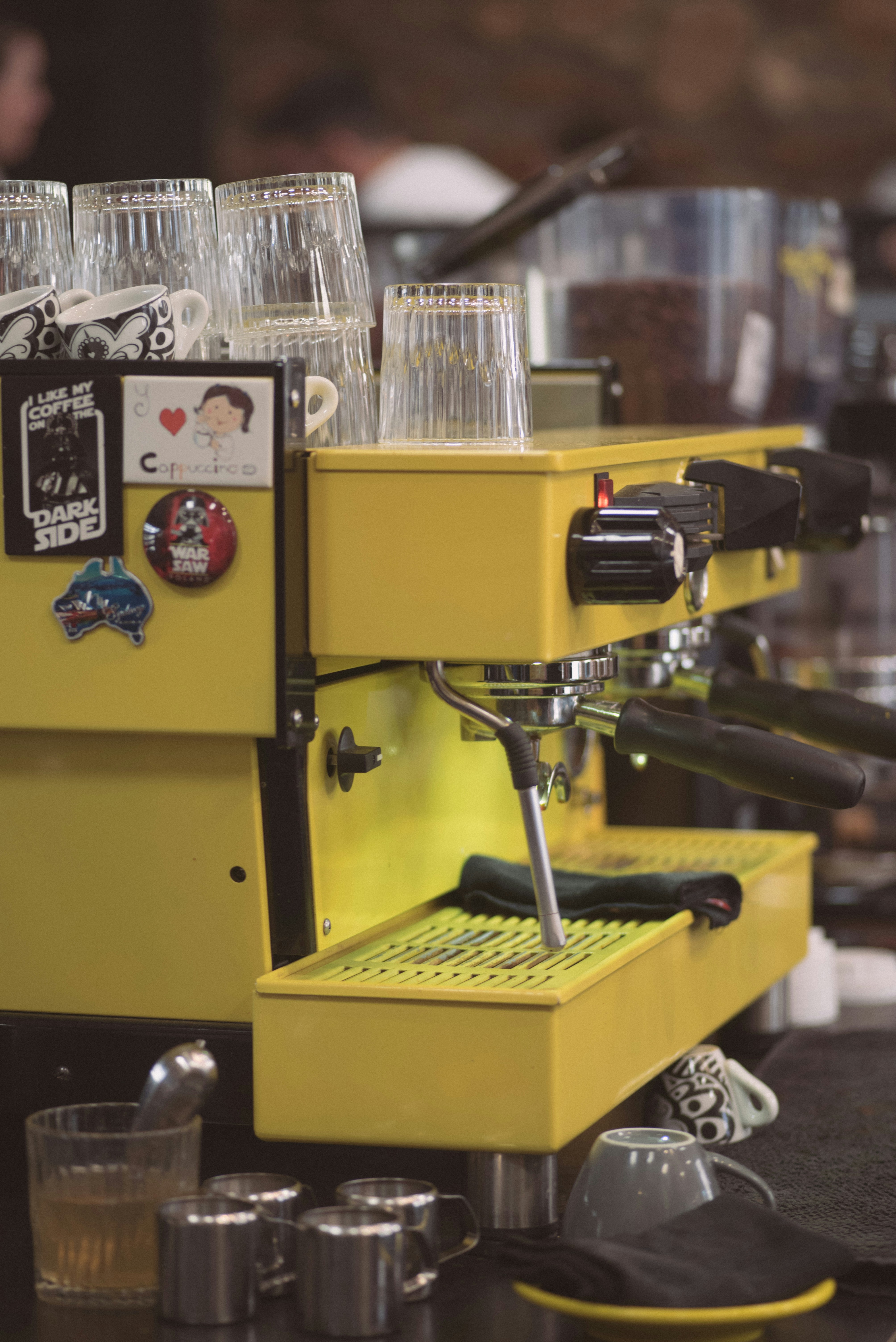 Yellow espresso machine with stacked glasses and coffee accessories