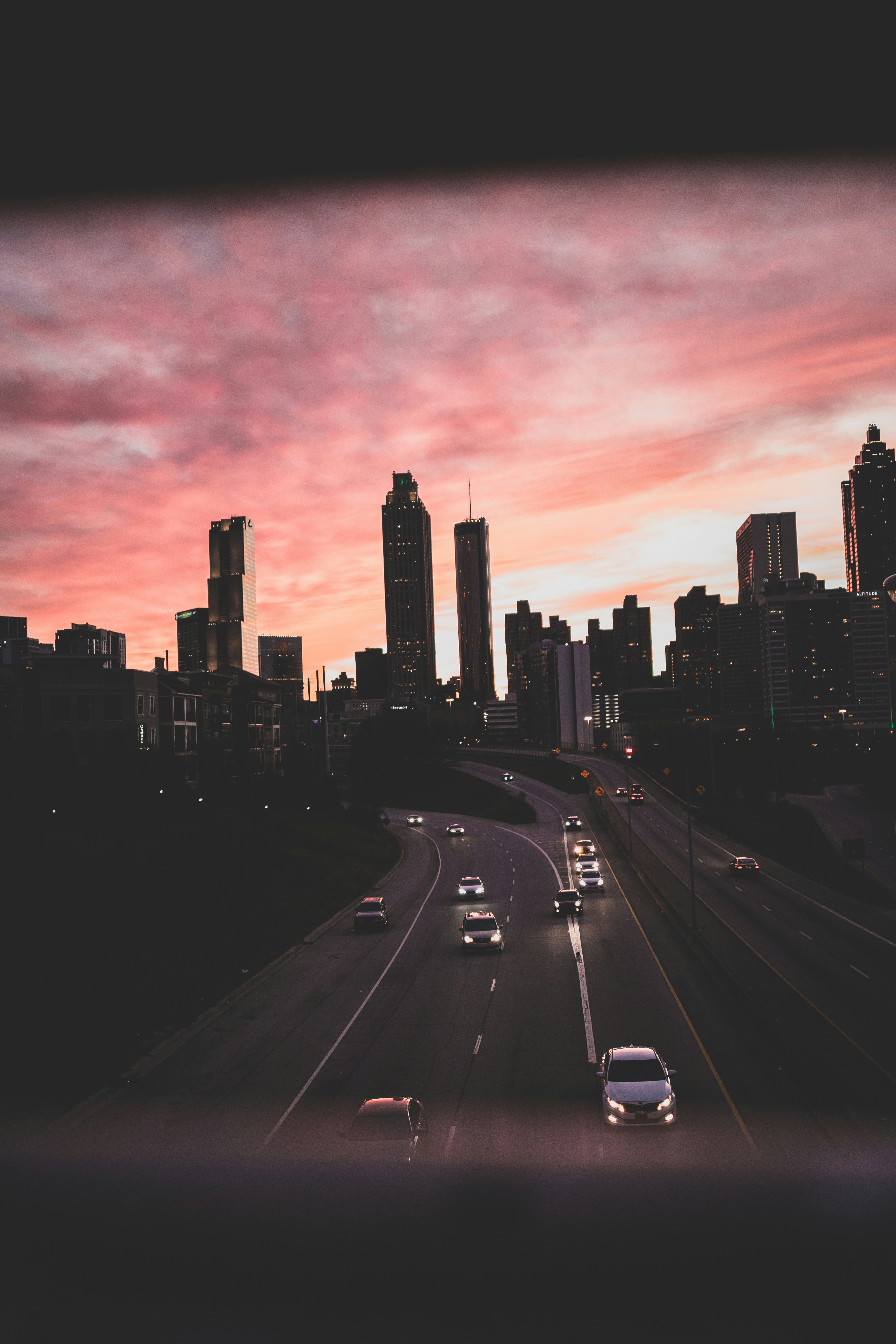 Crimson Dusk Over a Meandering Freeway Toward a Silhouetted Skyline