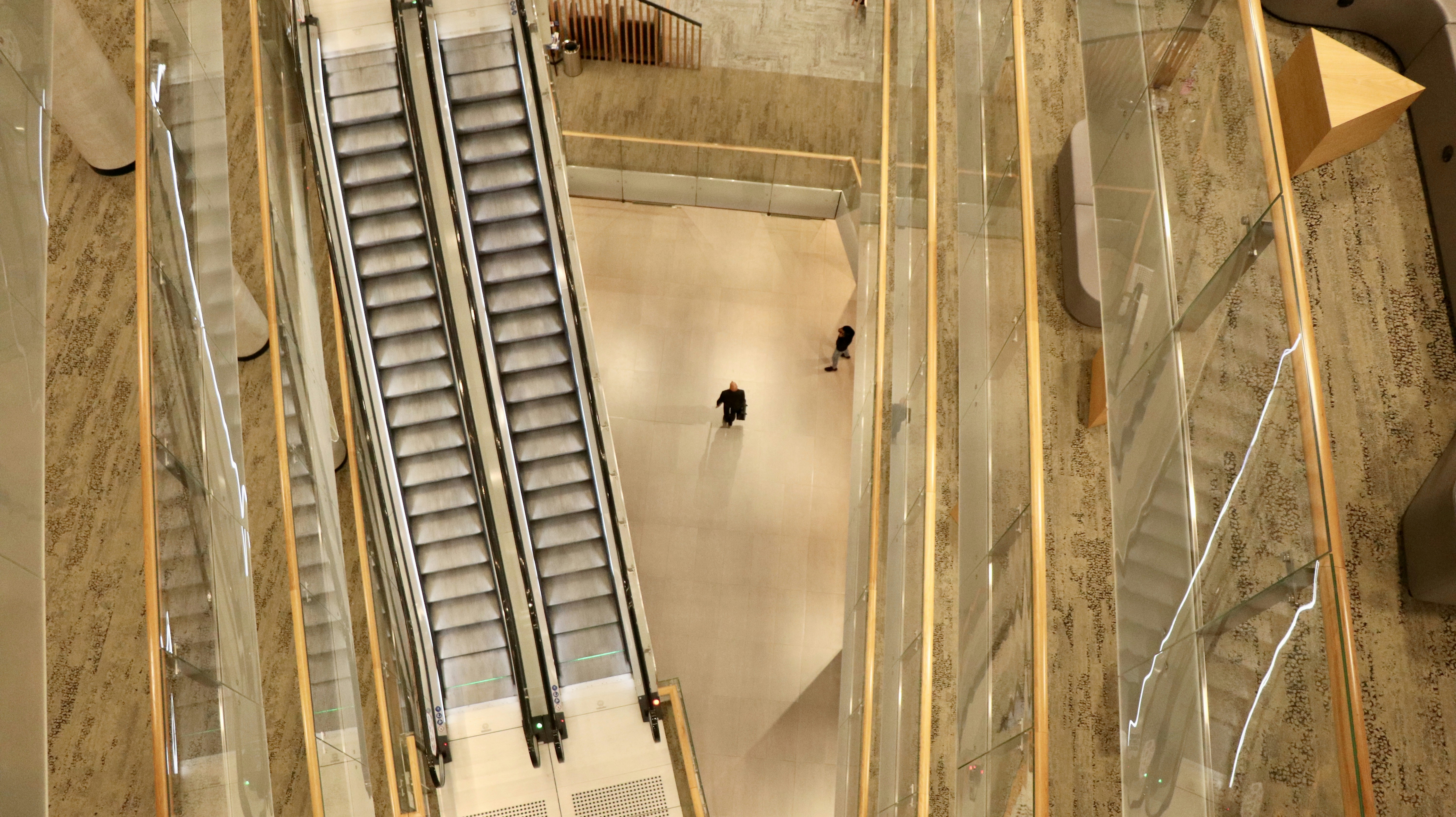 Modern architectural interior featuring escalators with a lone figure below, emphasizing the interplay of lines and light.