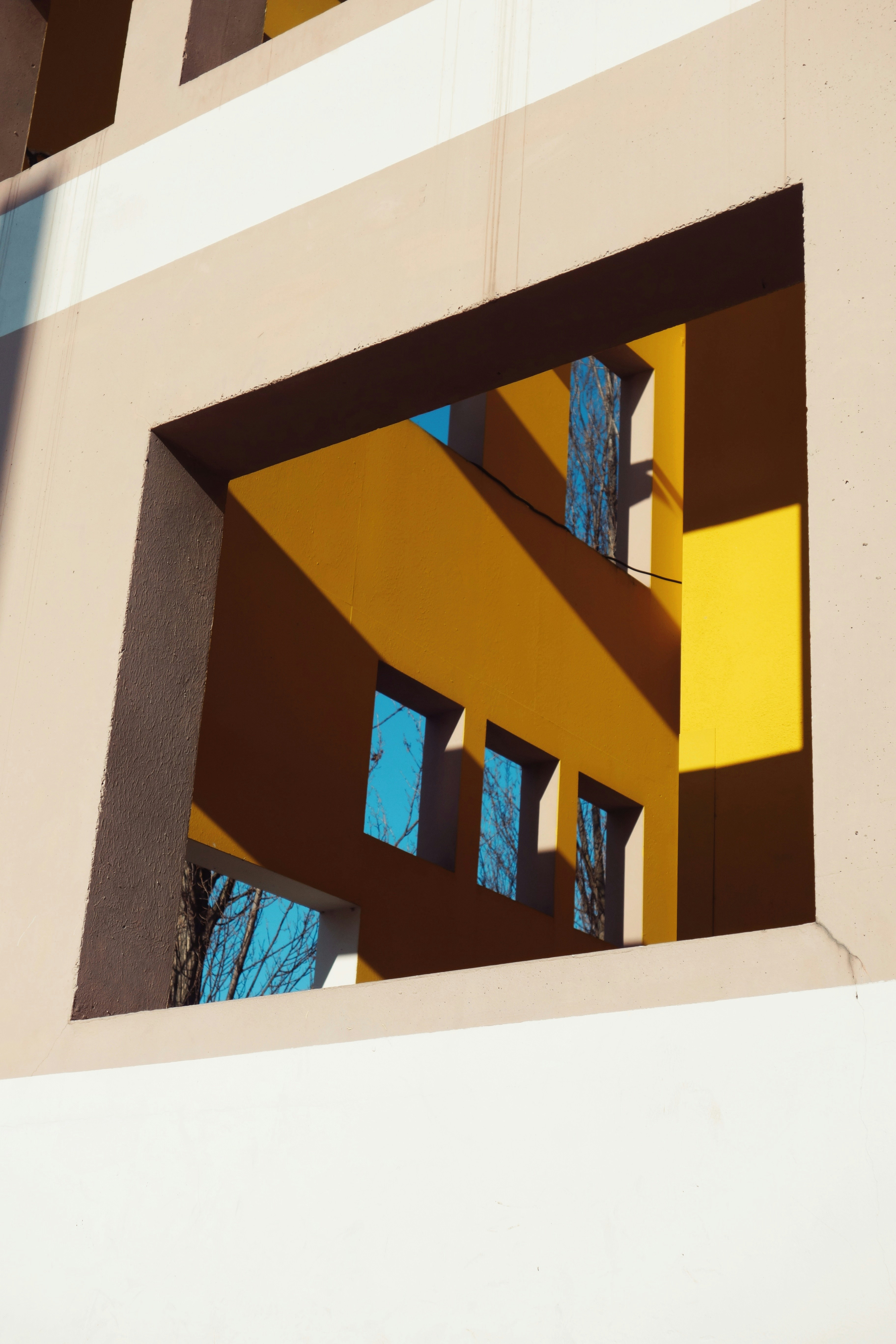 Abstract architectural composition featuring vibrant yellow and blue elements framed by geometric shapes. The interplay of light and shadow creates a dynamic visual experience.