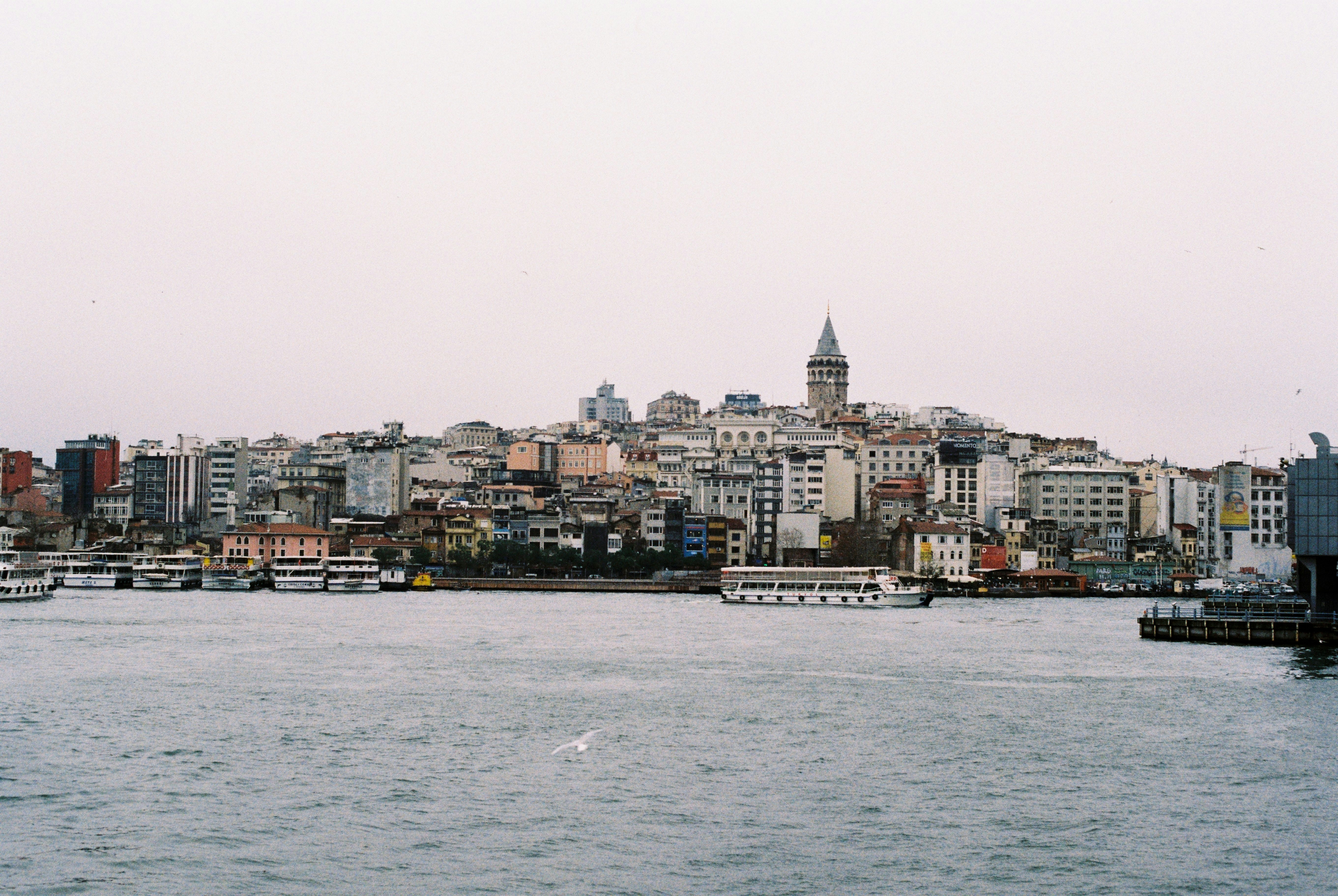 Cityscape with Galata Tower rising among diverse architecture along a waterfront.