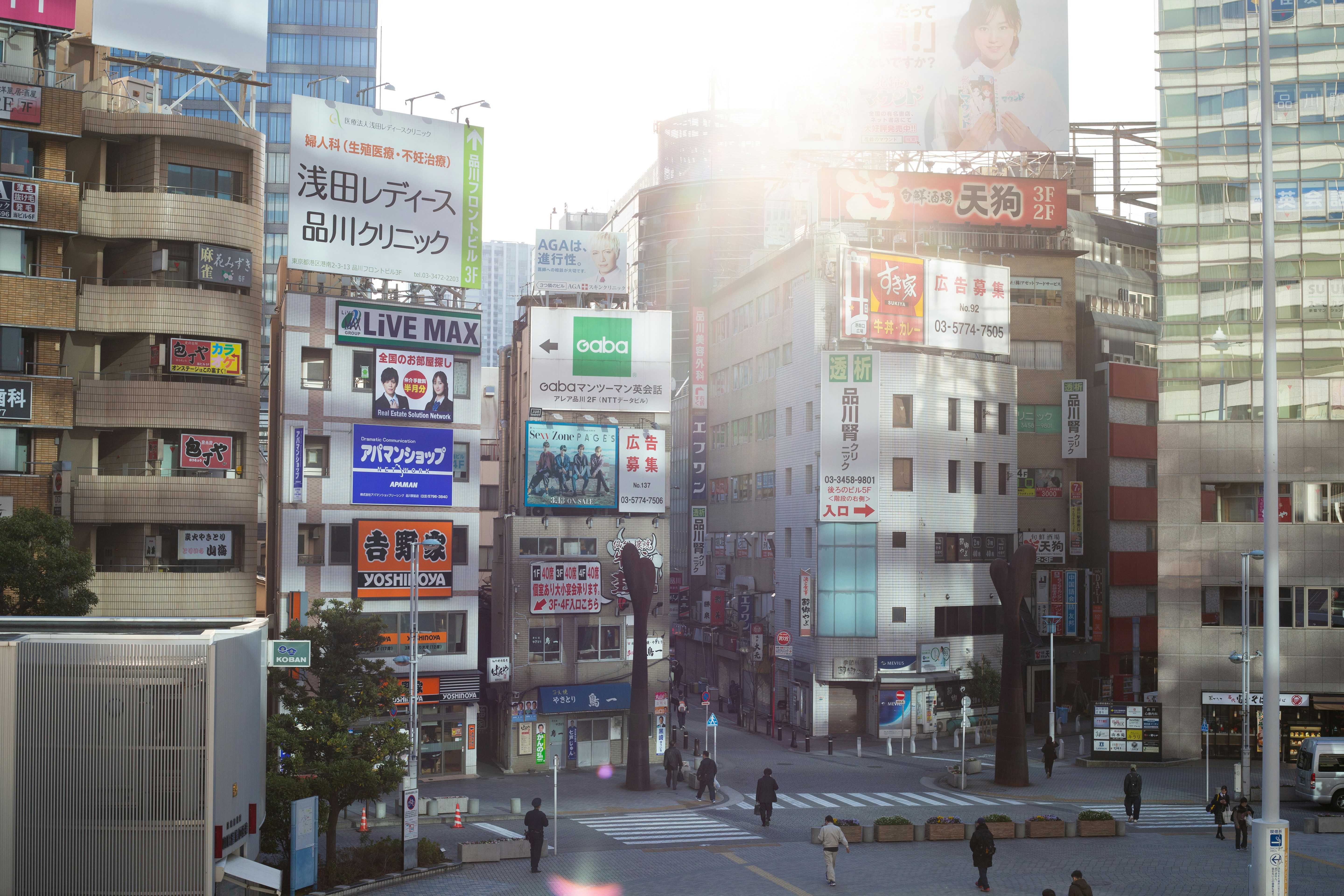 City street scene with colorful advertisements and buildings under bright sunlight.