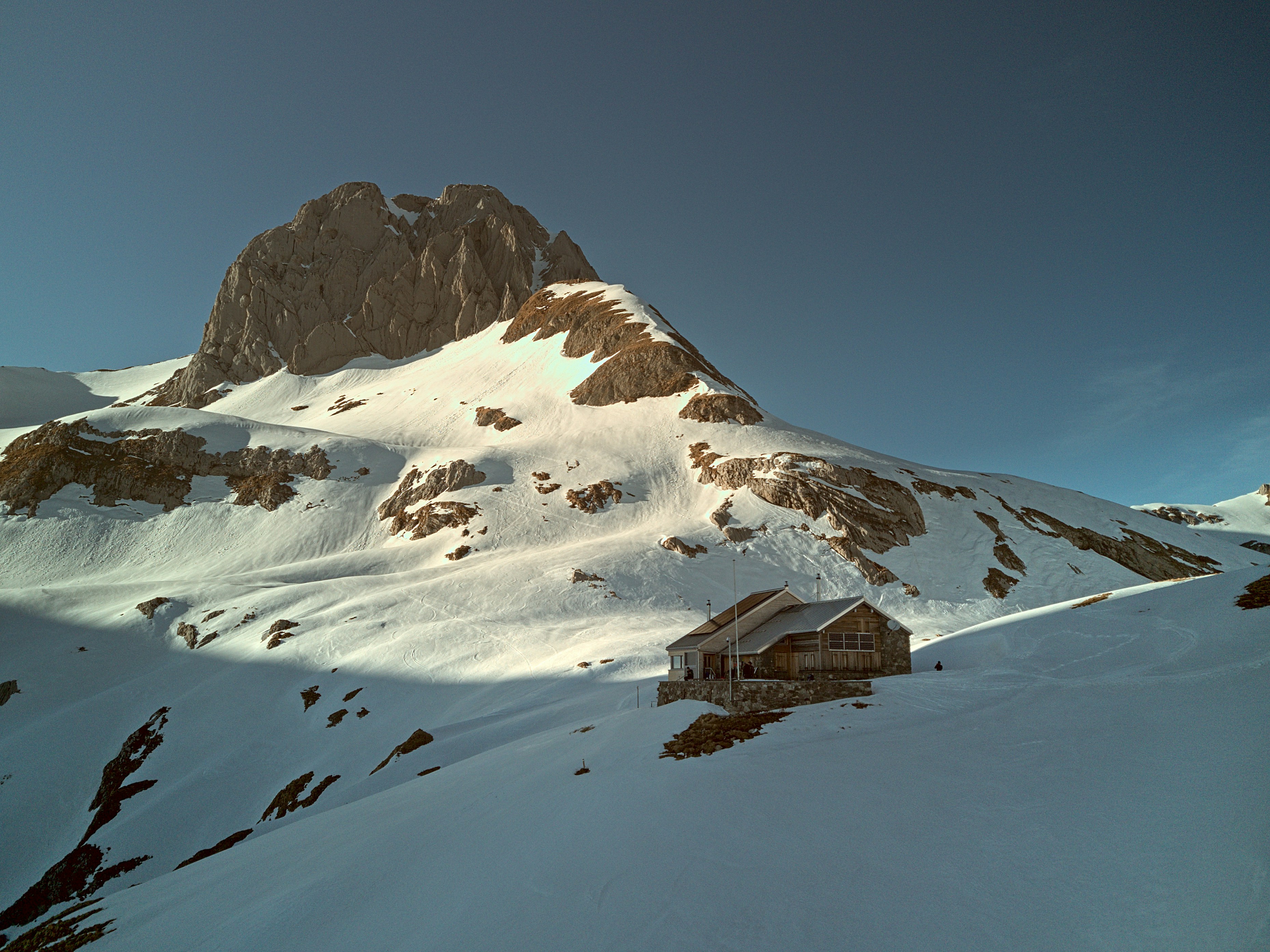 Brown rock mountain with the distance of green trees near body of water ...