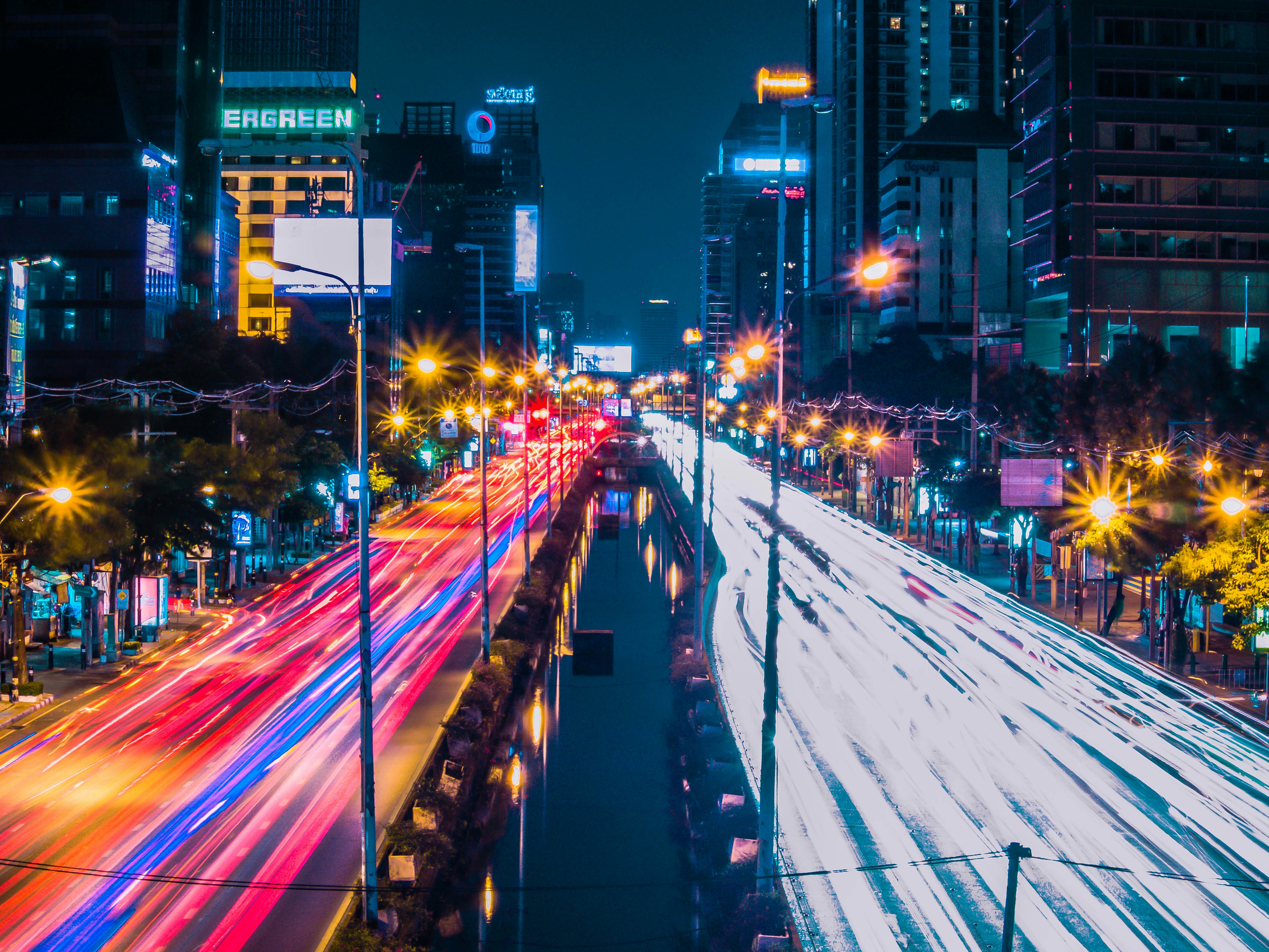 Vibrant light trails weave through a bustling city street at night.