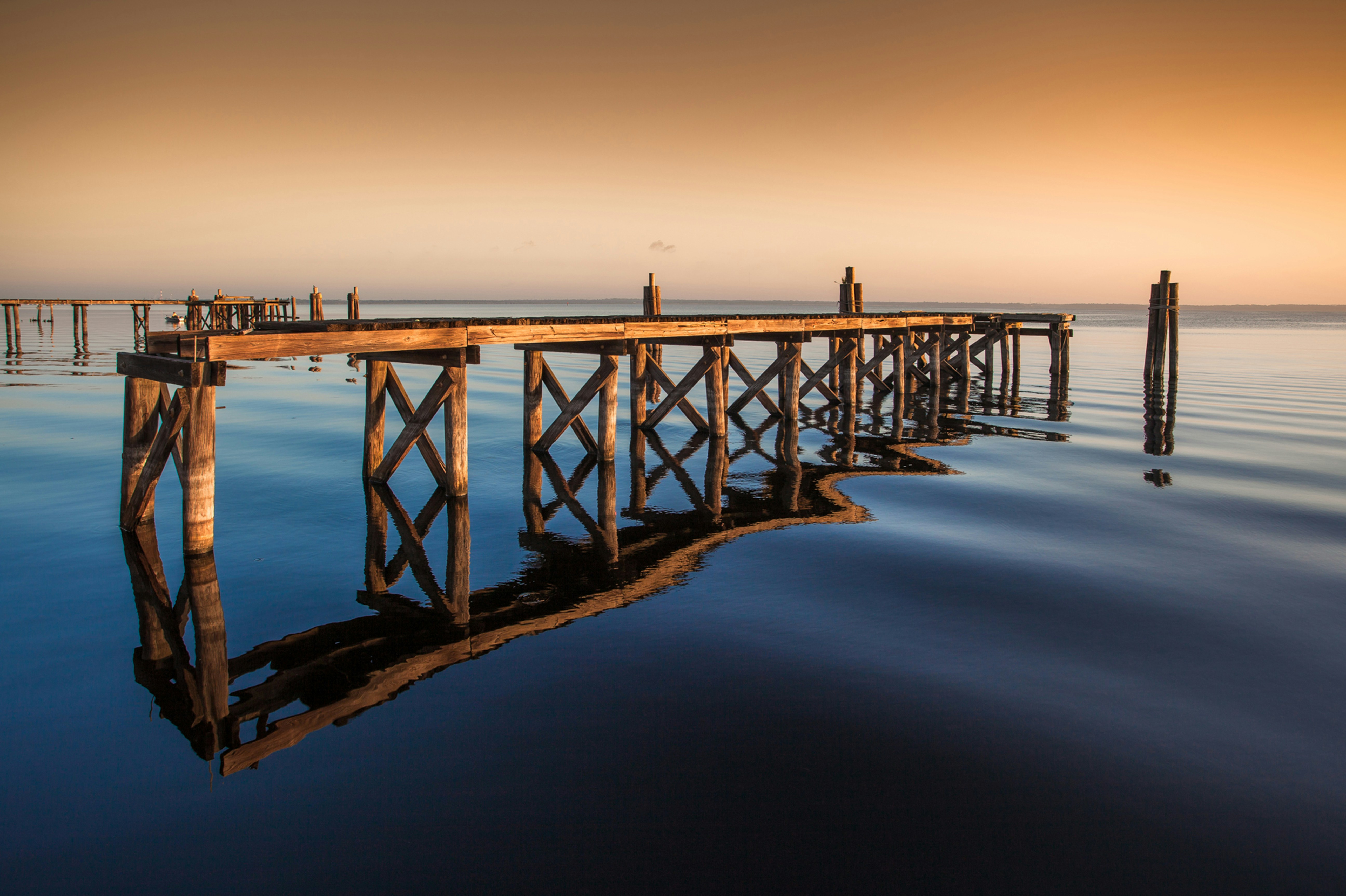 Wooden dock extending into calm waters, reflecting the serene colors of the twilight sky.