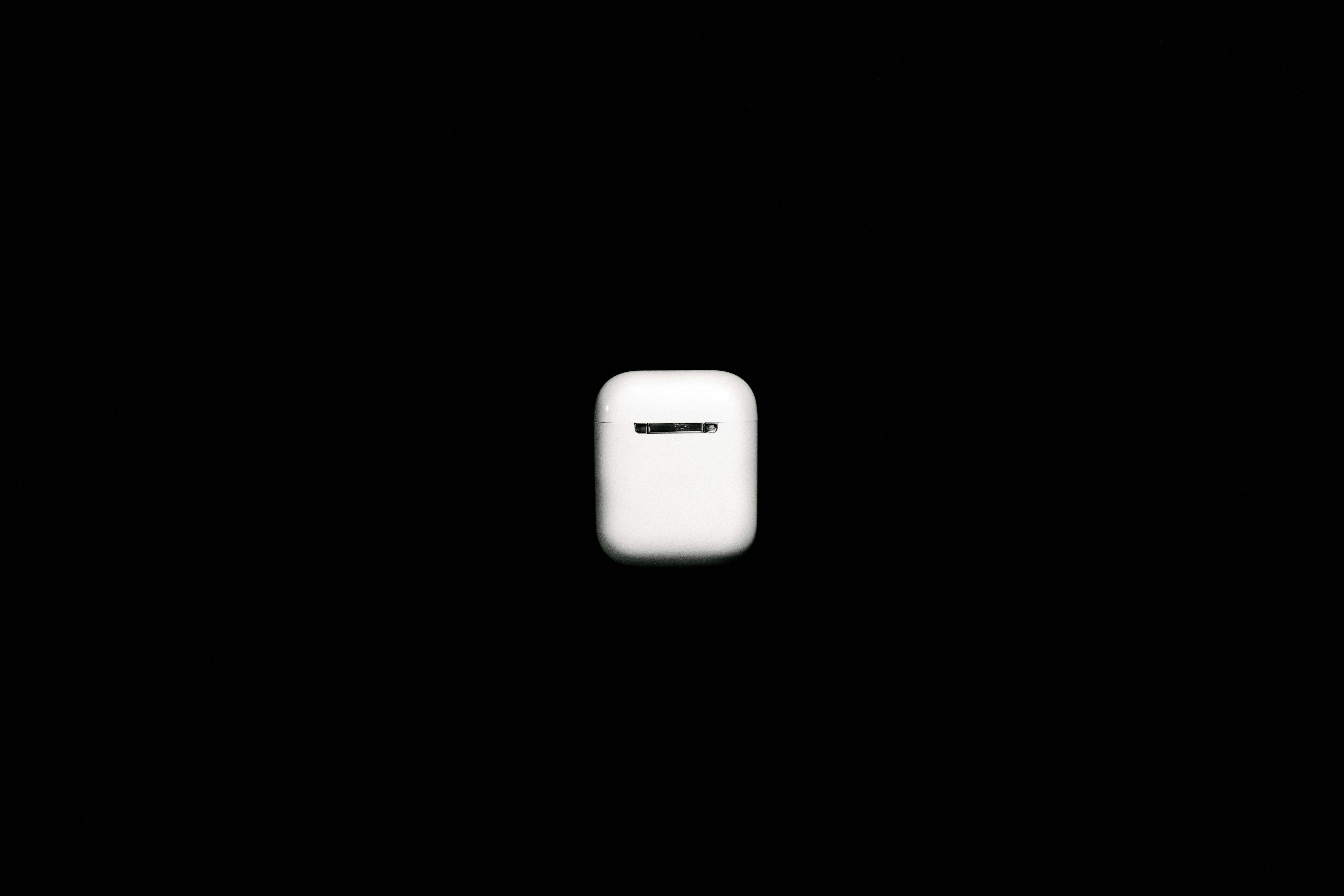 A pair of wireless earbuds nestled against a stark black background, emphasizing their sleek design and modern aesthetic.