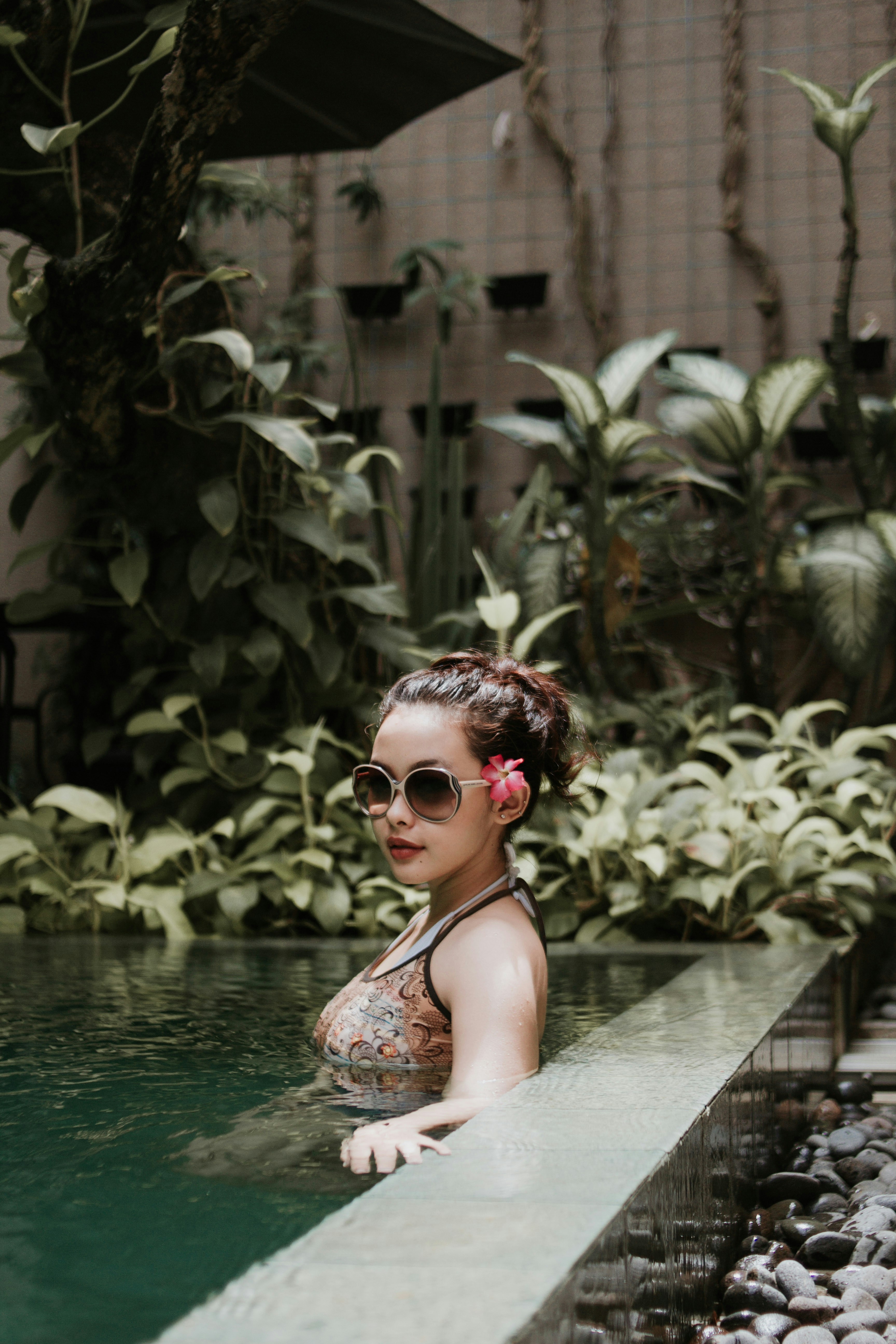 Sunglasses and Orchid: A Poolside Portrait Amid Tropical Foliage
