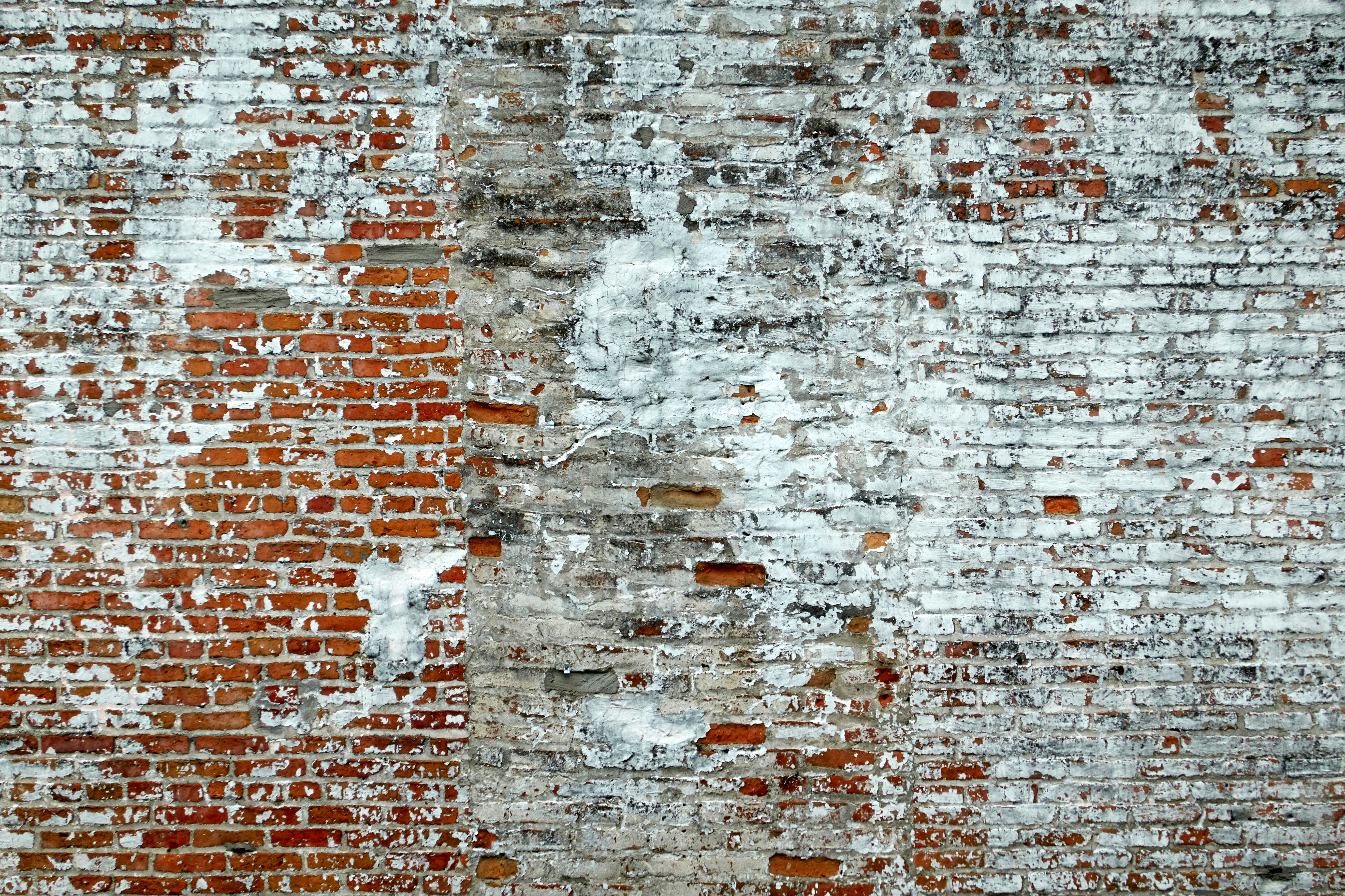 A weathered brick wall showcasing a blend of red and white textures, revealing layers of history and character.