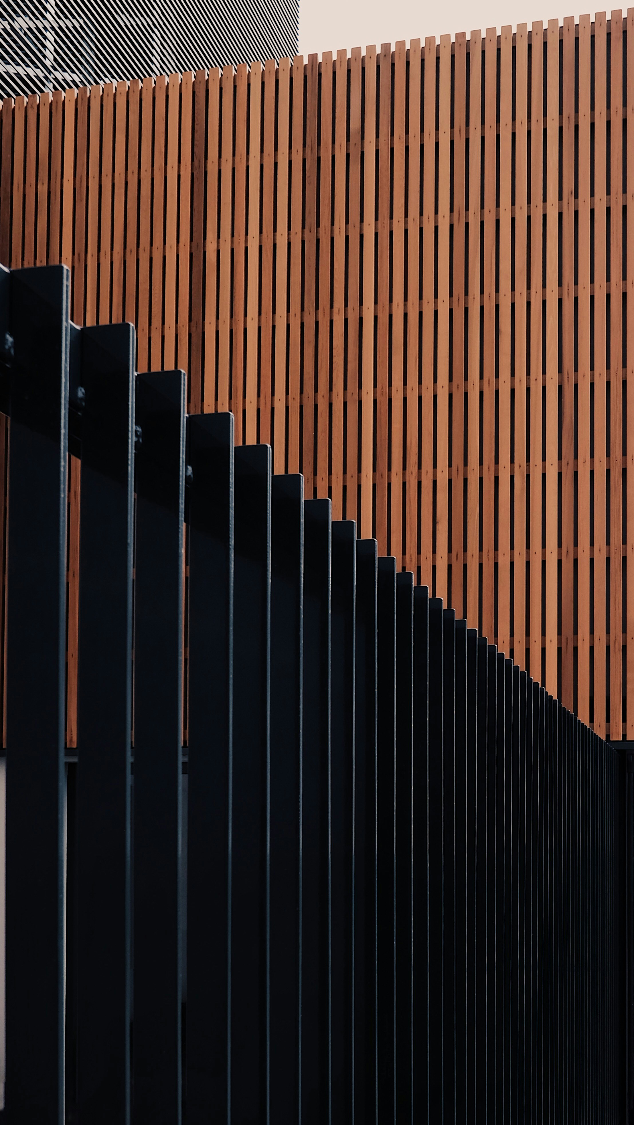Abstract composition showcasing the interplay of black vertical slats and warm wooden panels in a modern architectural setting.