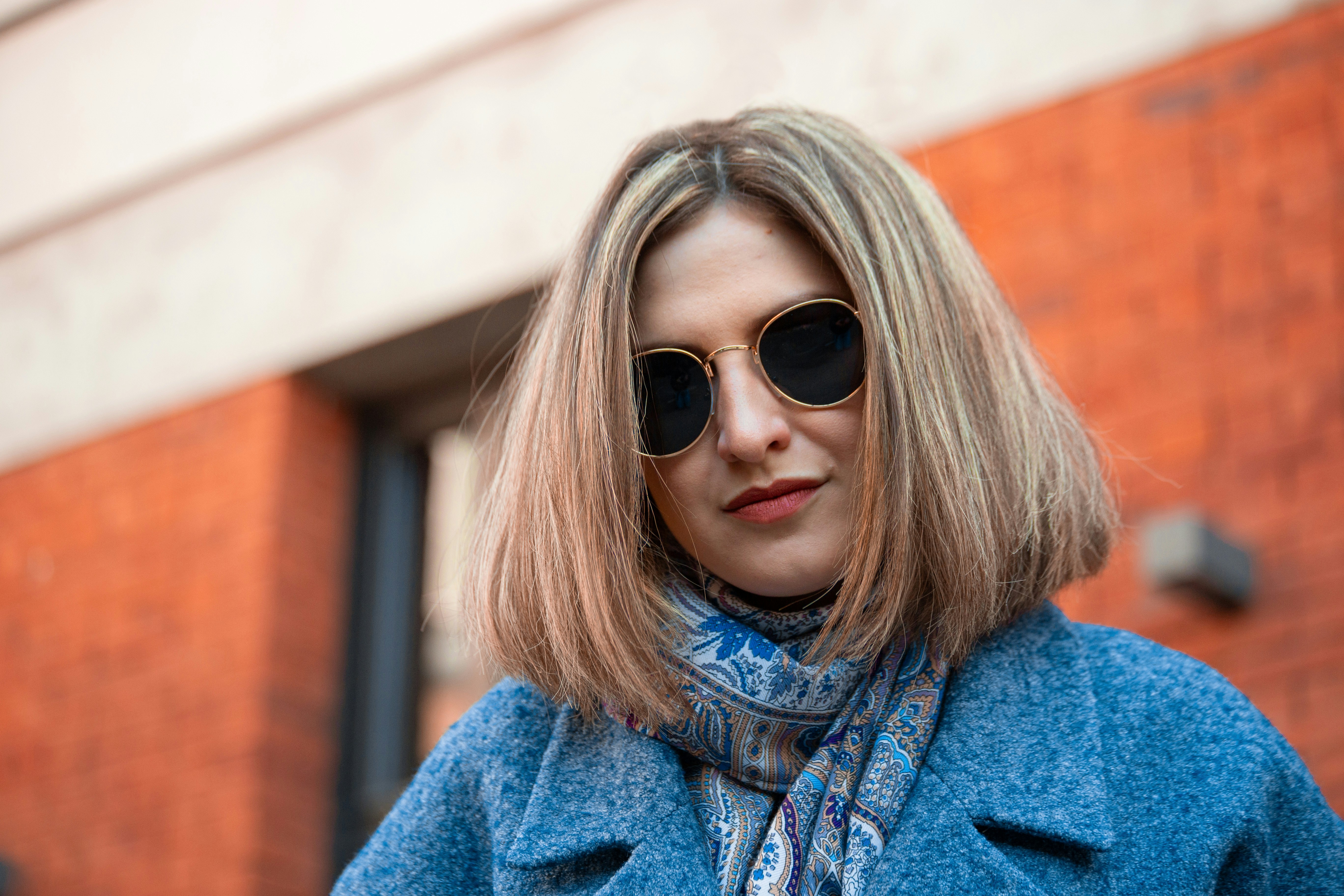 woman in blue coat wearing sunglasses