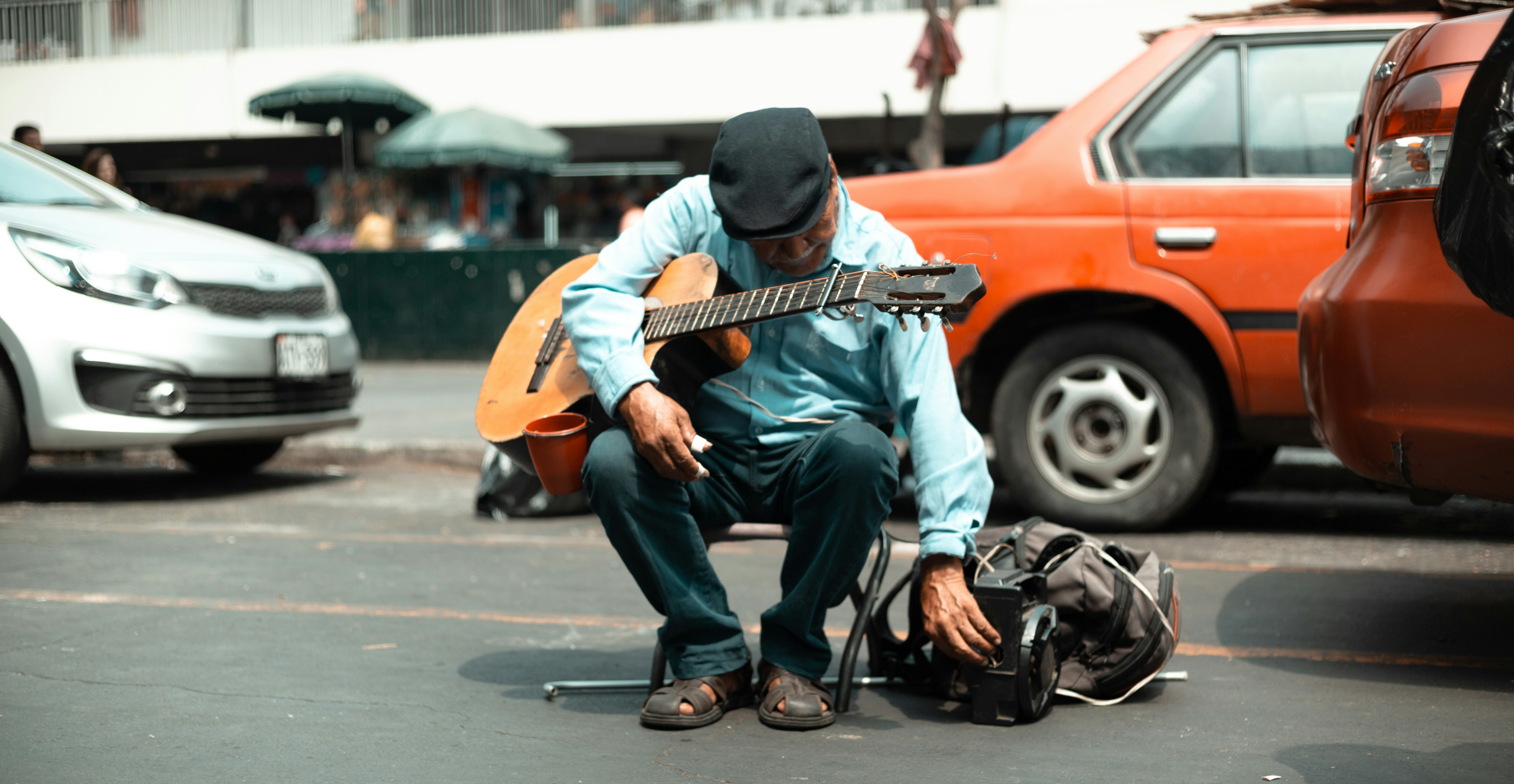 man sitting on street holding guitar