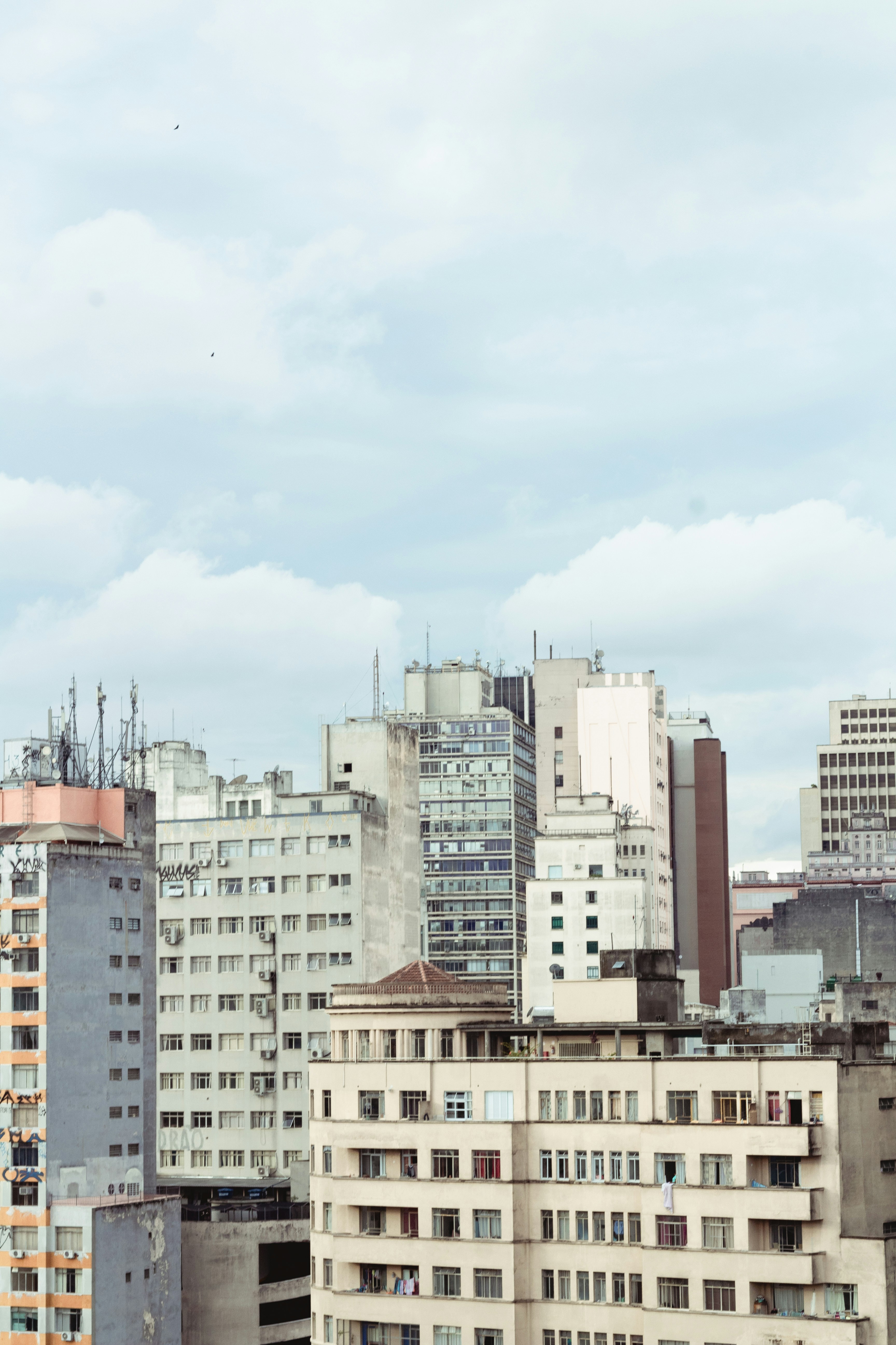 A panoramic view of a city skyline showcasing a mix of modern and vintage architecture against a cloudy sky.