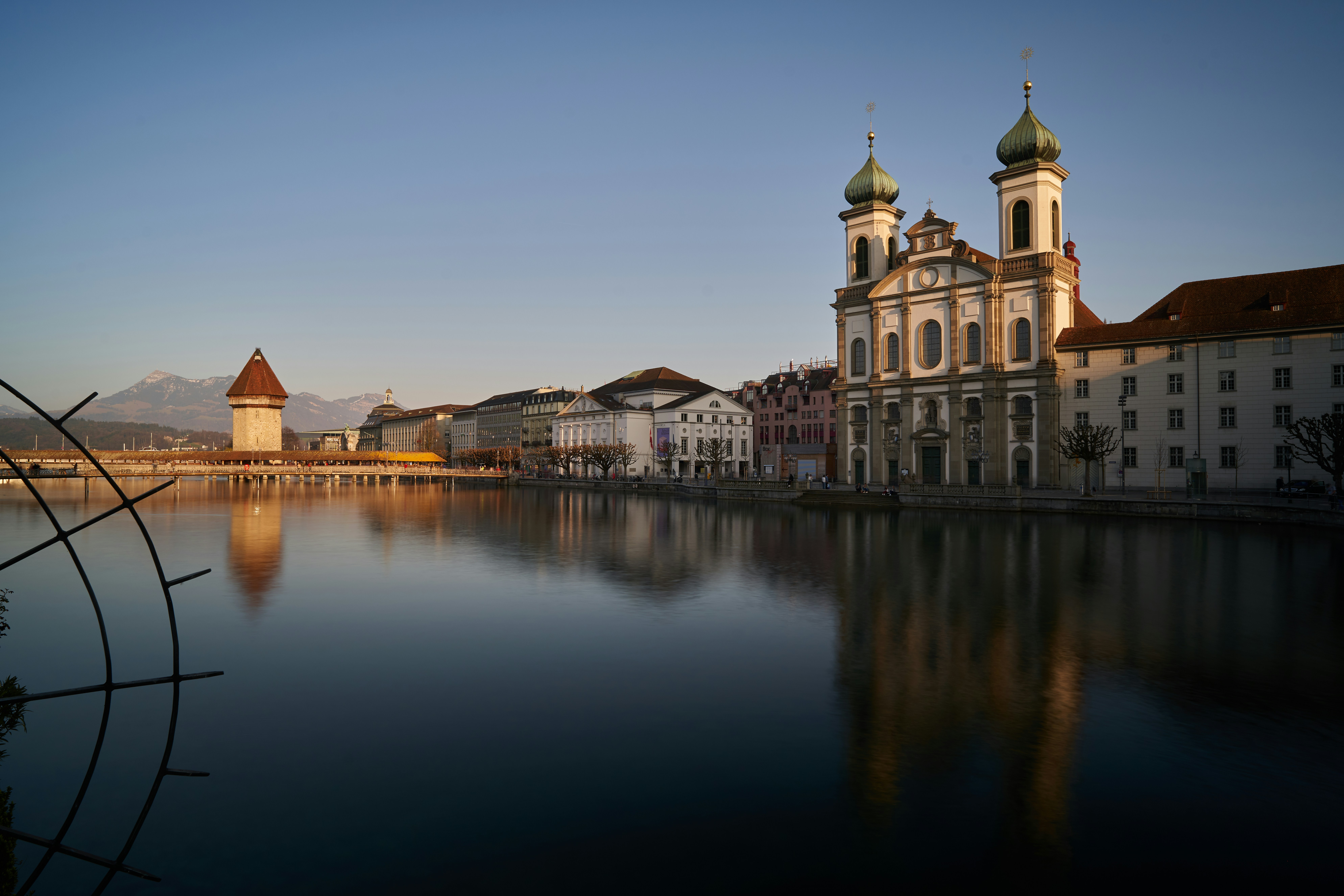 Jesuit church and surrounding architecture reflected in calm water at sunset.