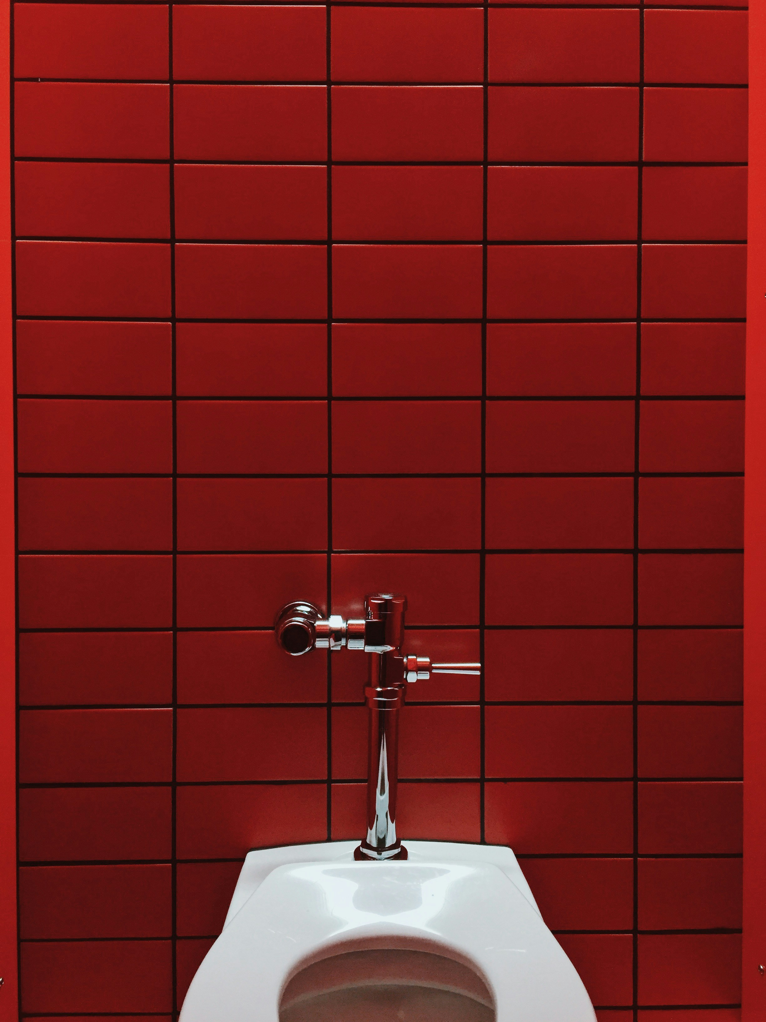 Crimson Grid: A Lone Chrome Faucet Anchoring a Red Wall